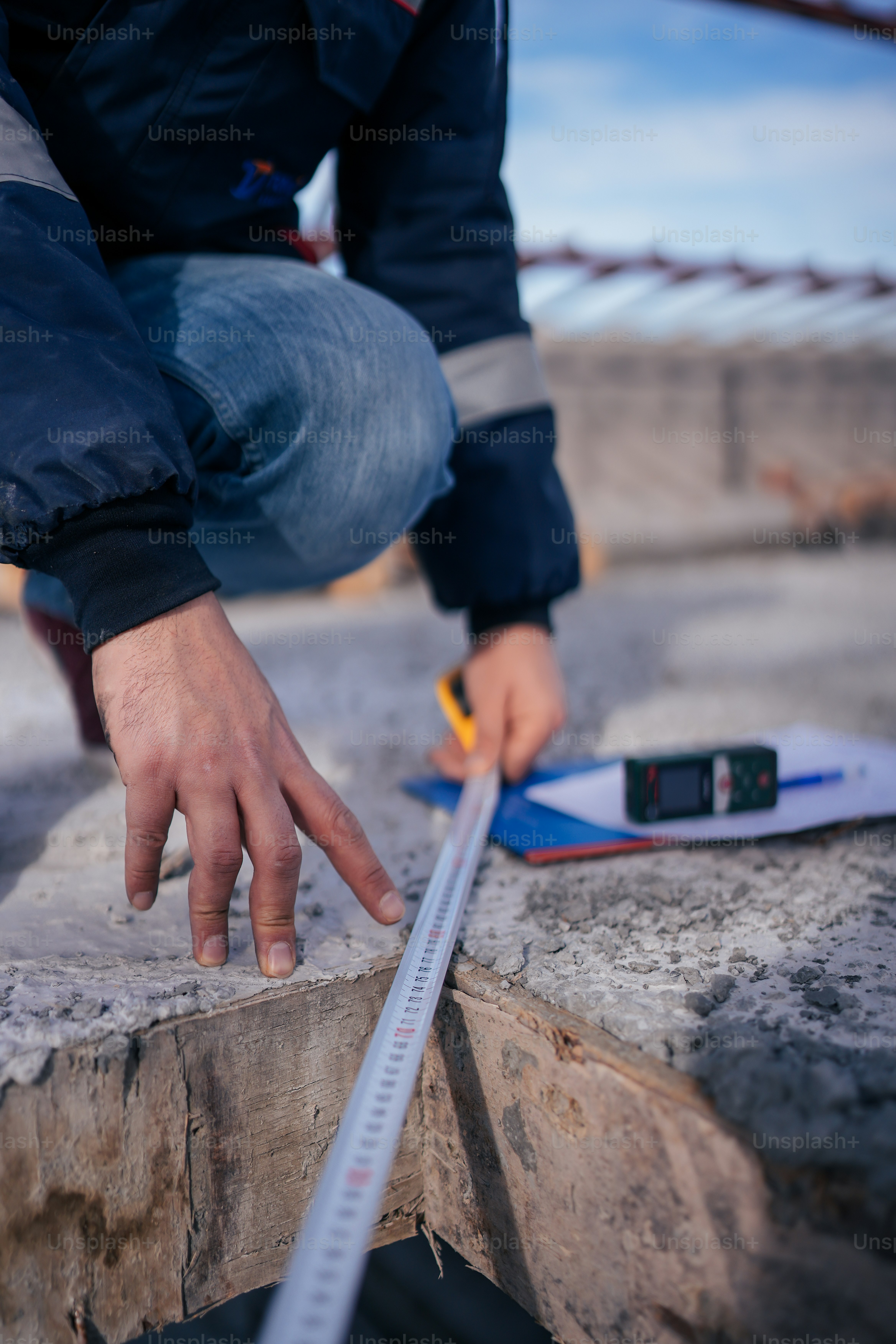 A person holding a measuring tape over a piece of wood photo ...
