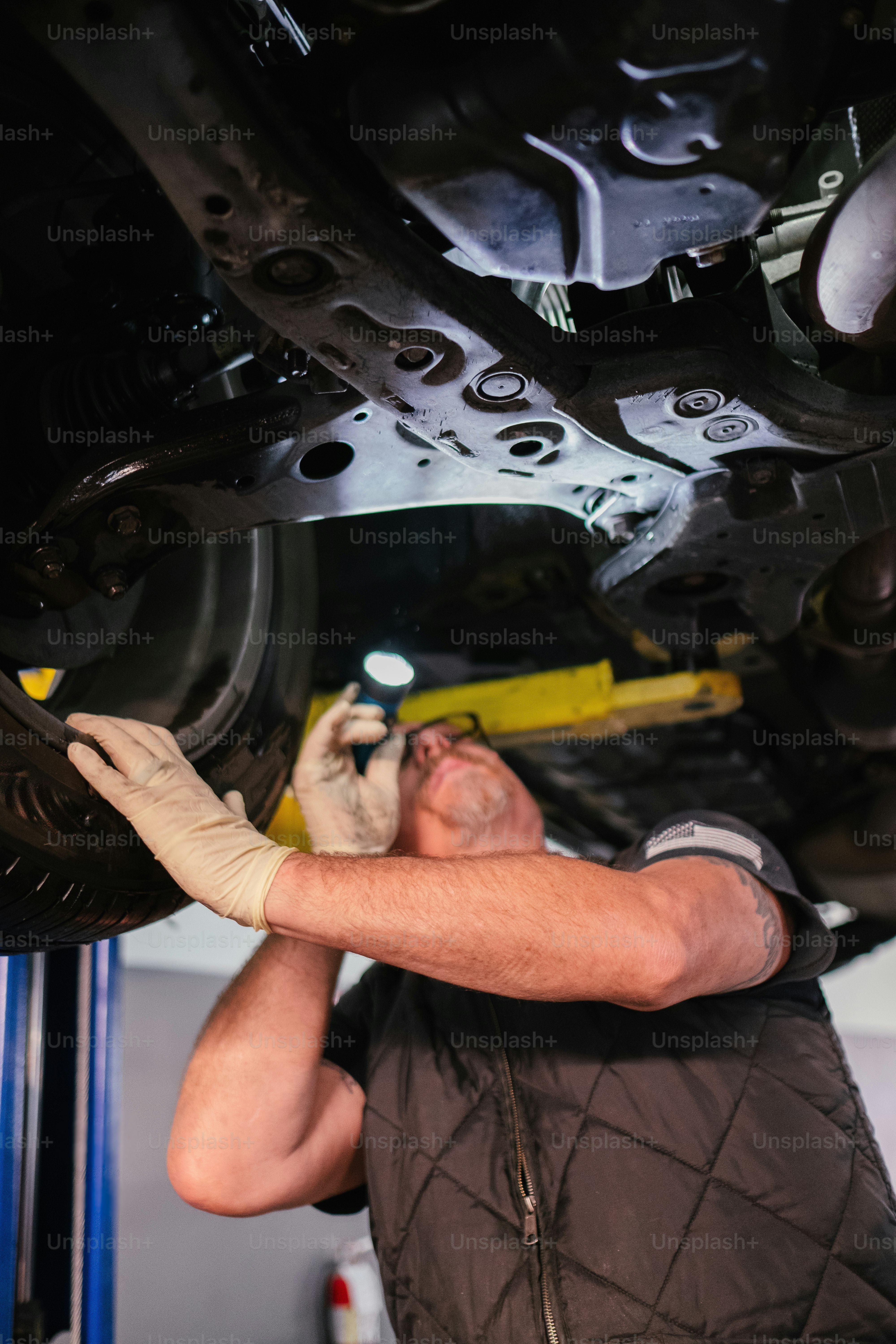 A man working on a car engine in a garage photo – Mechanic Image on ...