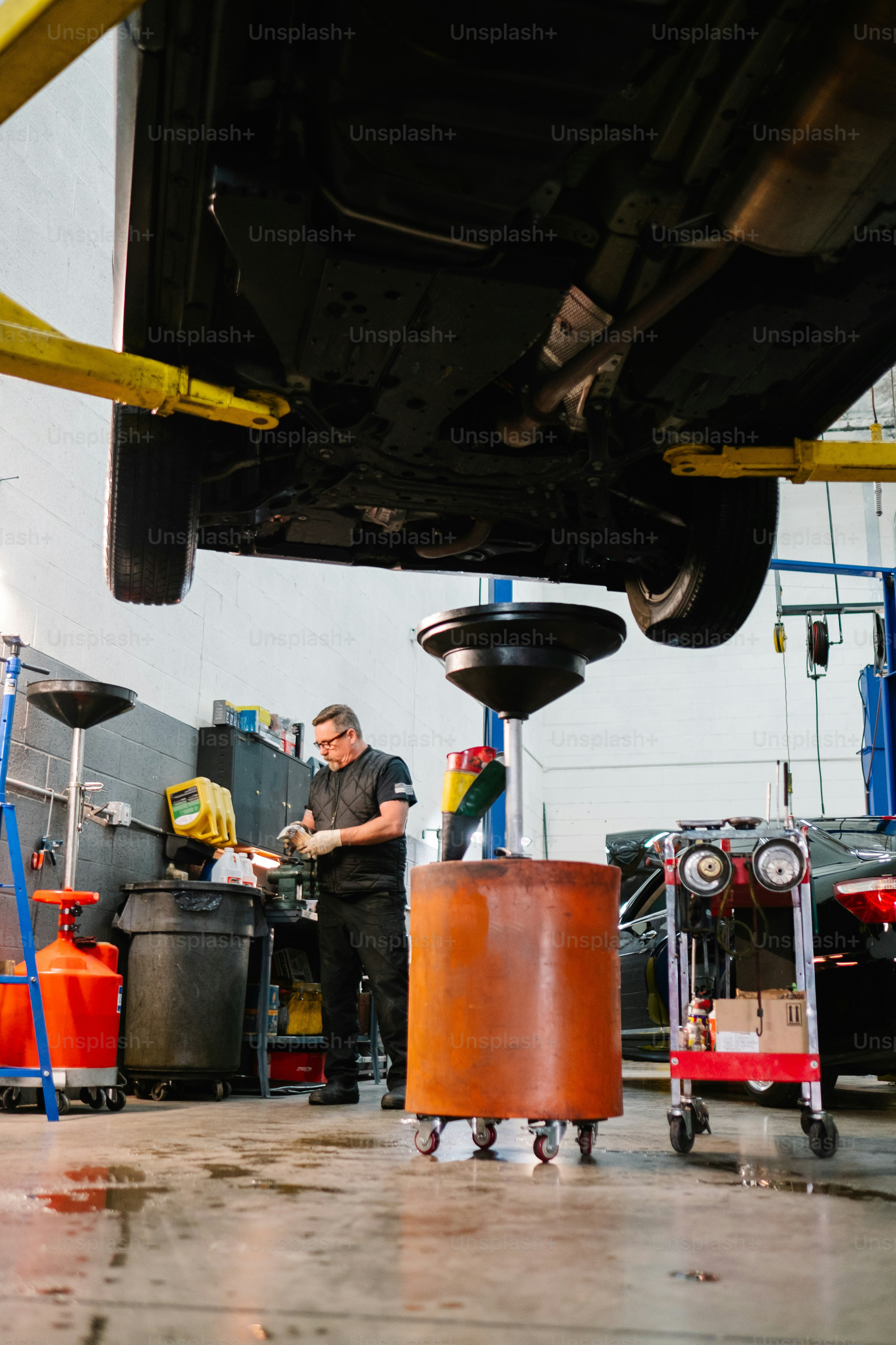 A man working on a car engine in a garage photo – Mechanic Image on ...