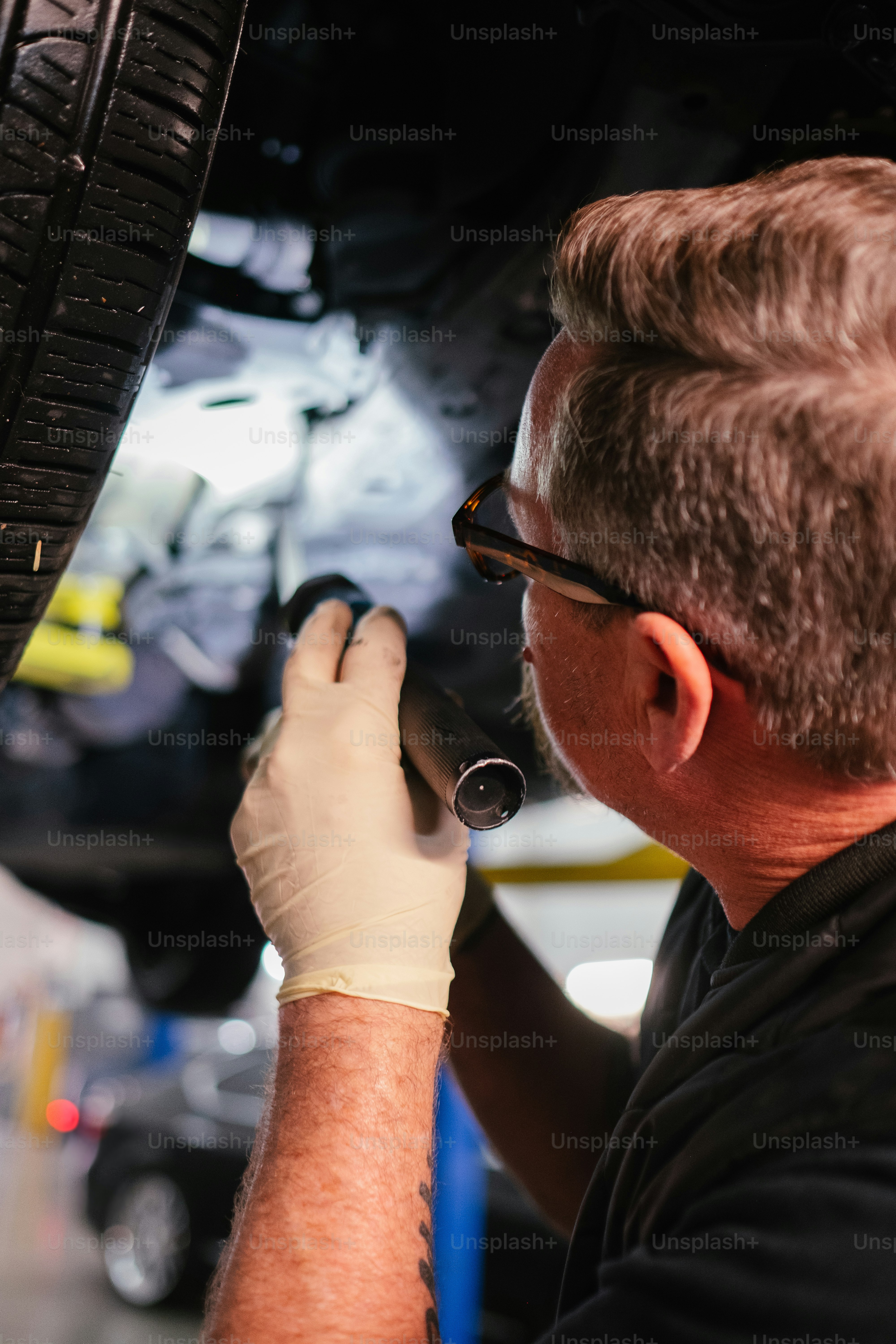A man working on a car engine in a garage photo – Mechanic Image on ...