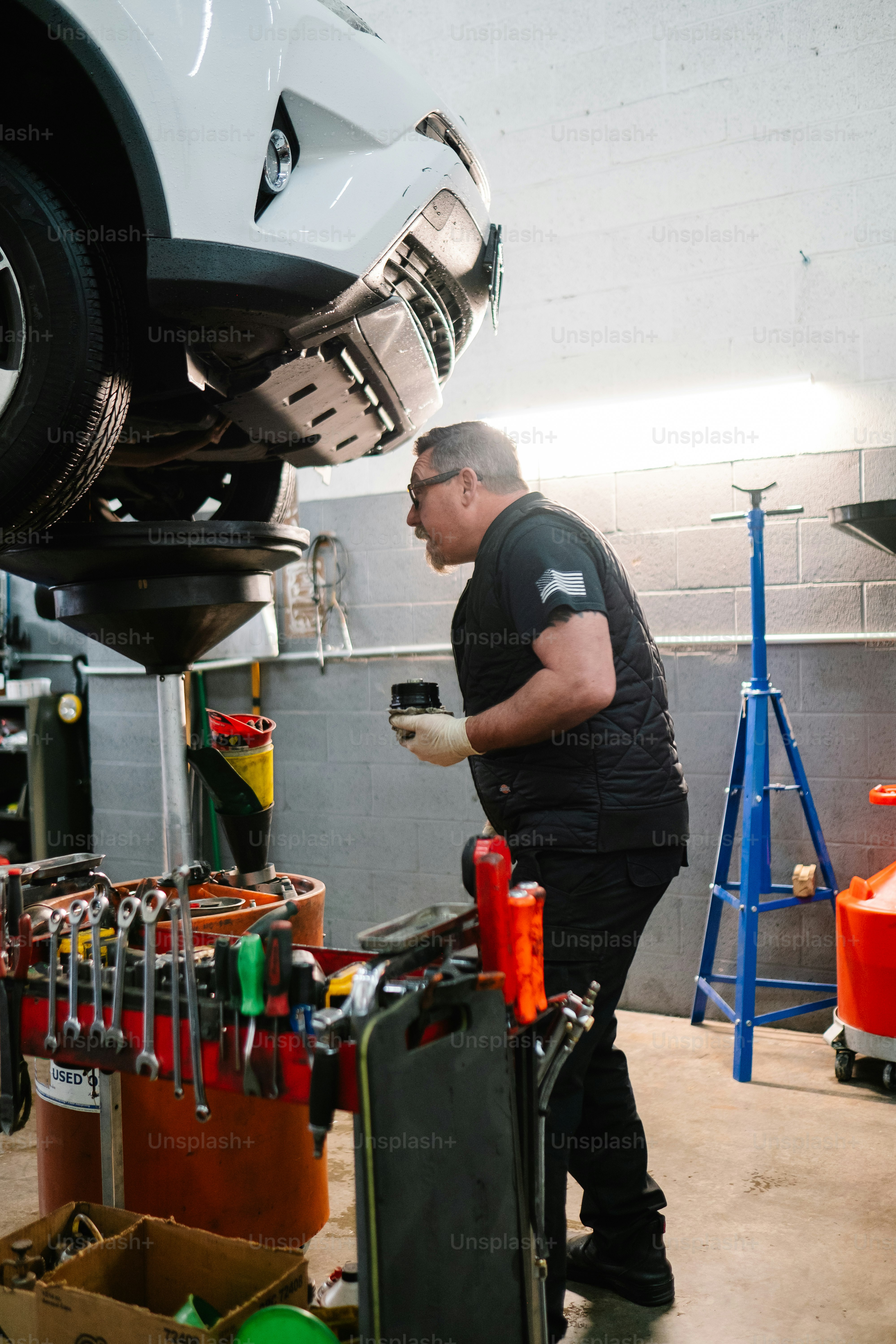 A man working on a car engine in a garage photo – Professional Image on ...