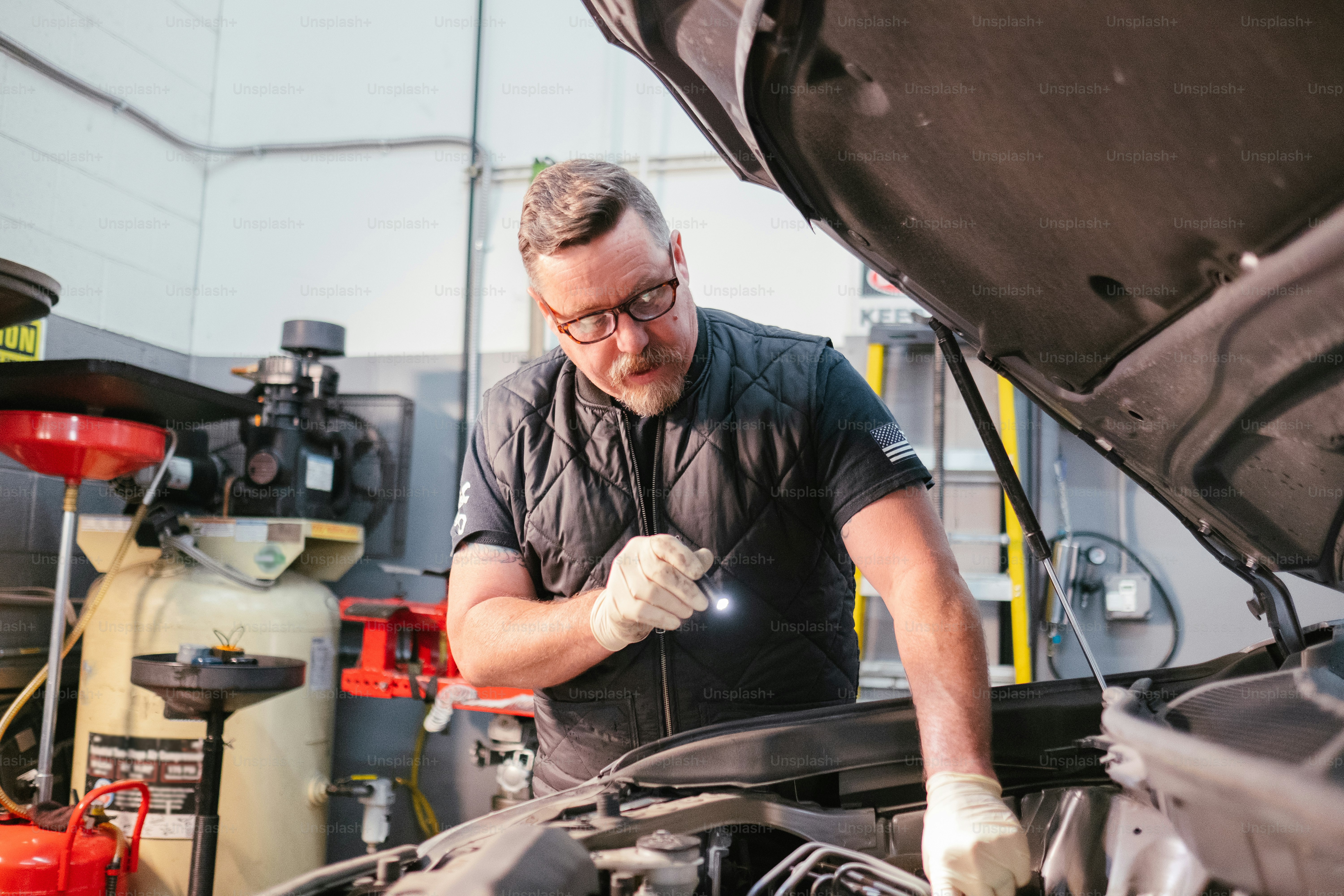A man working on a car in a garage photo – Car mechanic Image on Unsplash