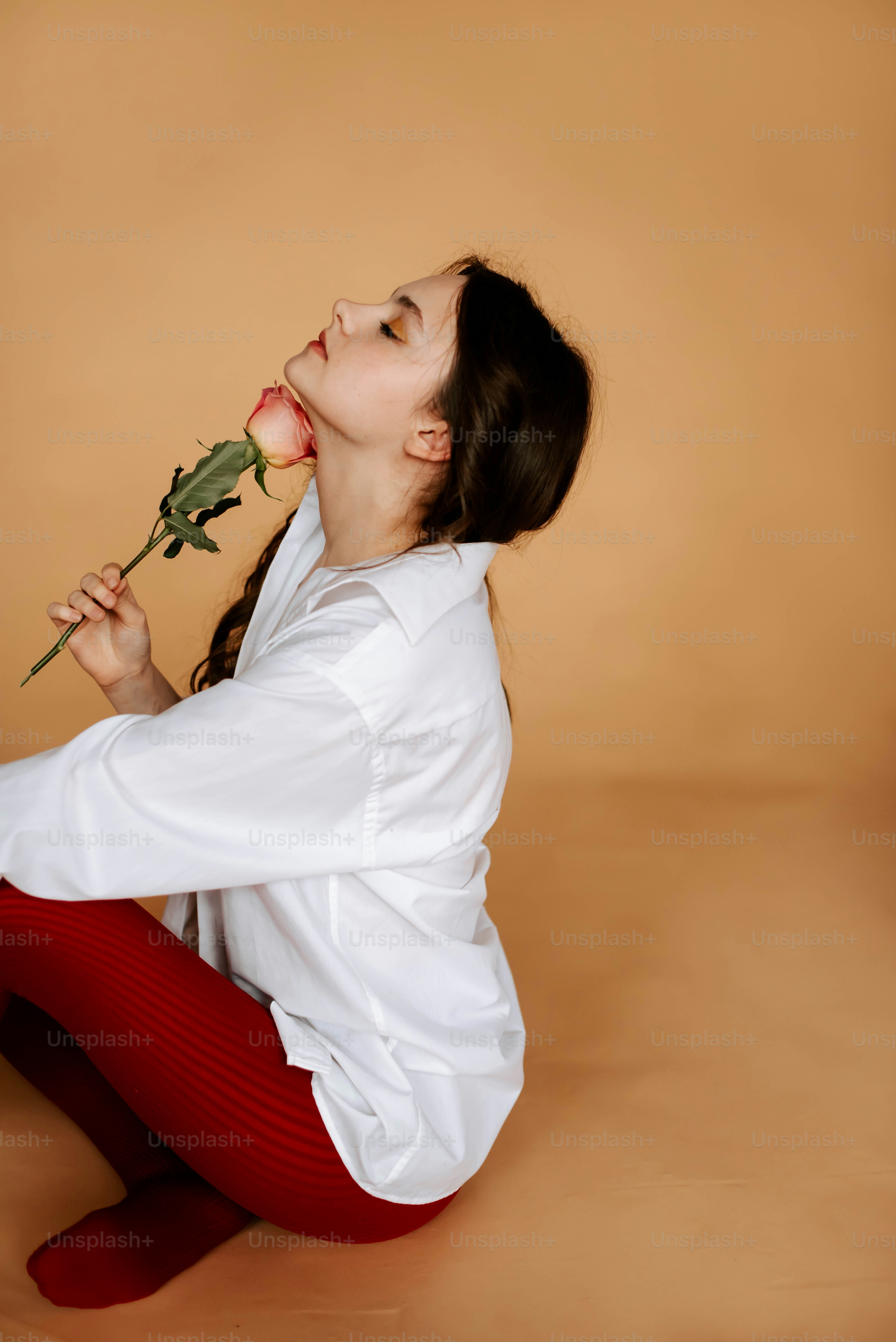 A woman sitting on the floor with a rose in her mouth photo – Female ...
