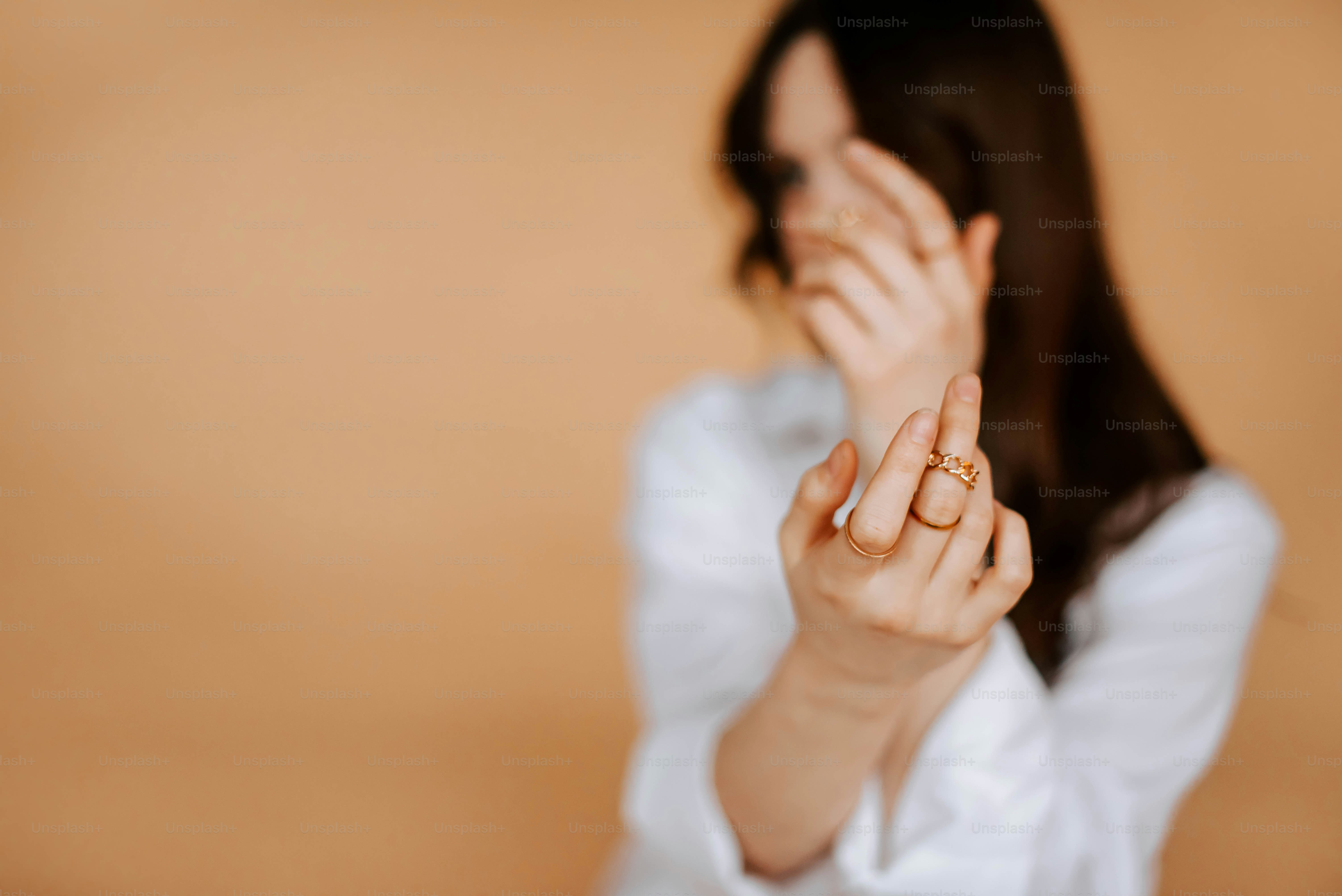 A woman making a hand gesture with her fingers photo – Tan background ...