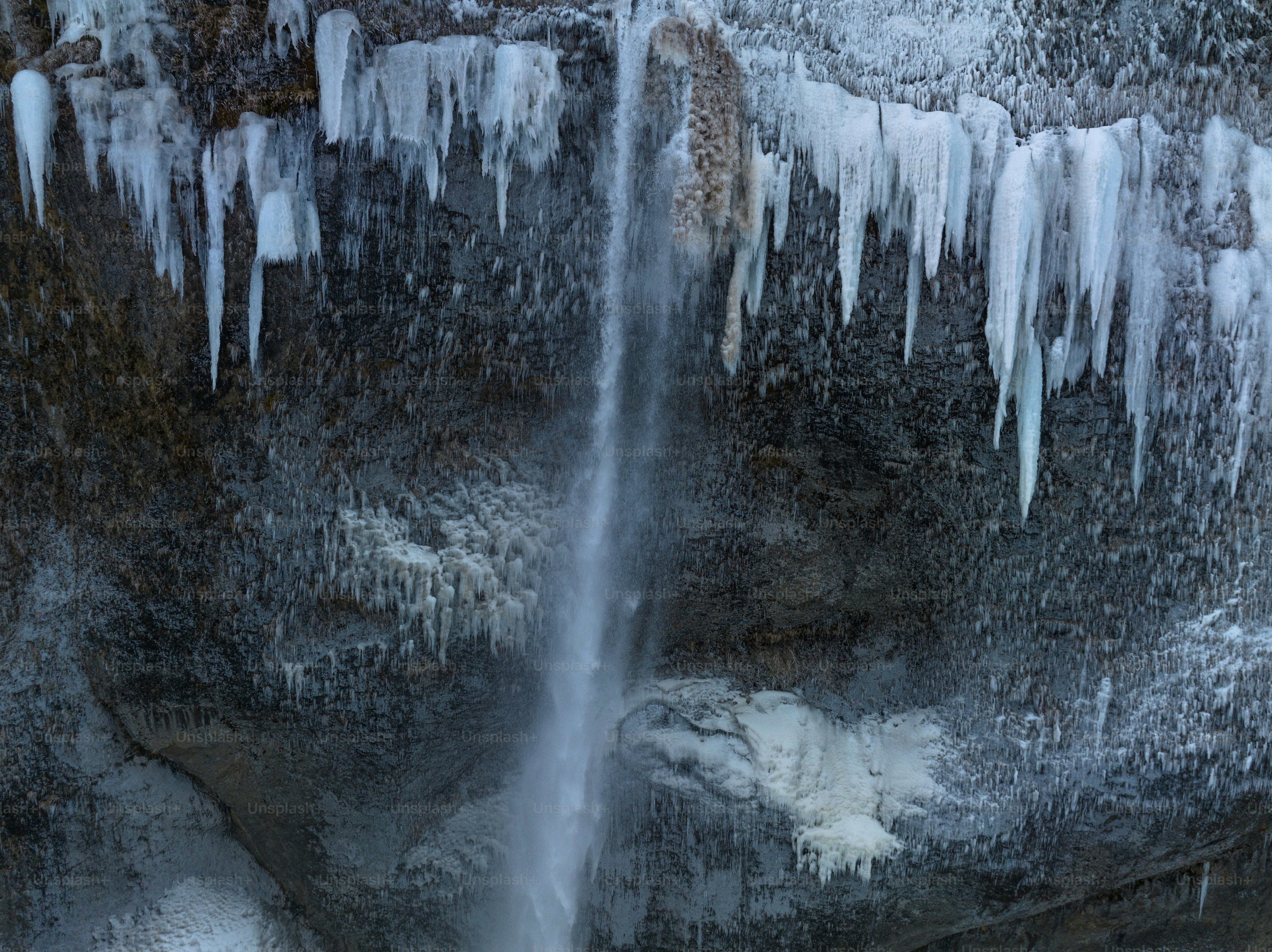 A waterfall with ice hanging off of it's sides photo – Ice Image on ...