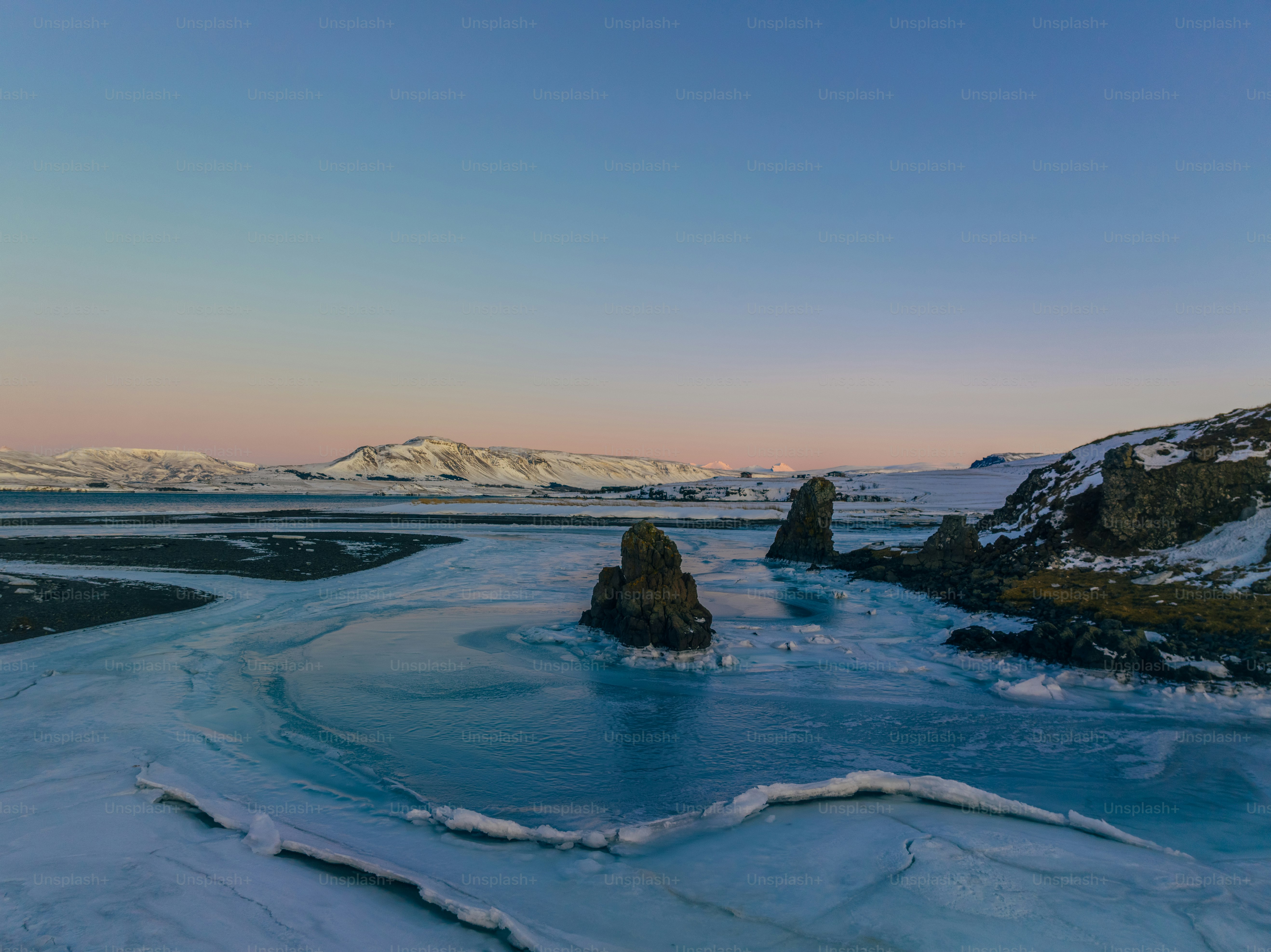 A body of water surrounded by snow covered mountains photo – Screen ...