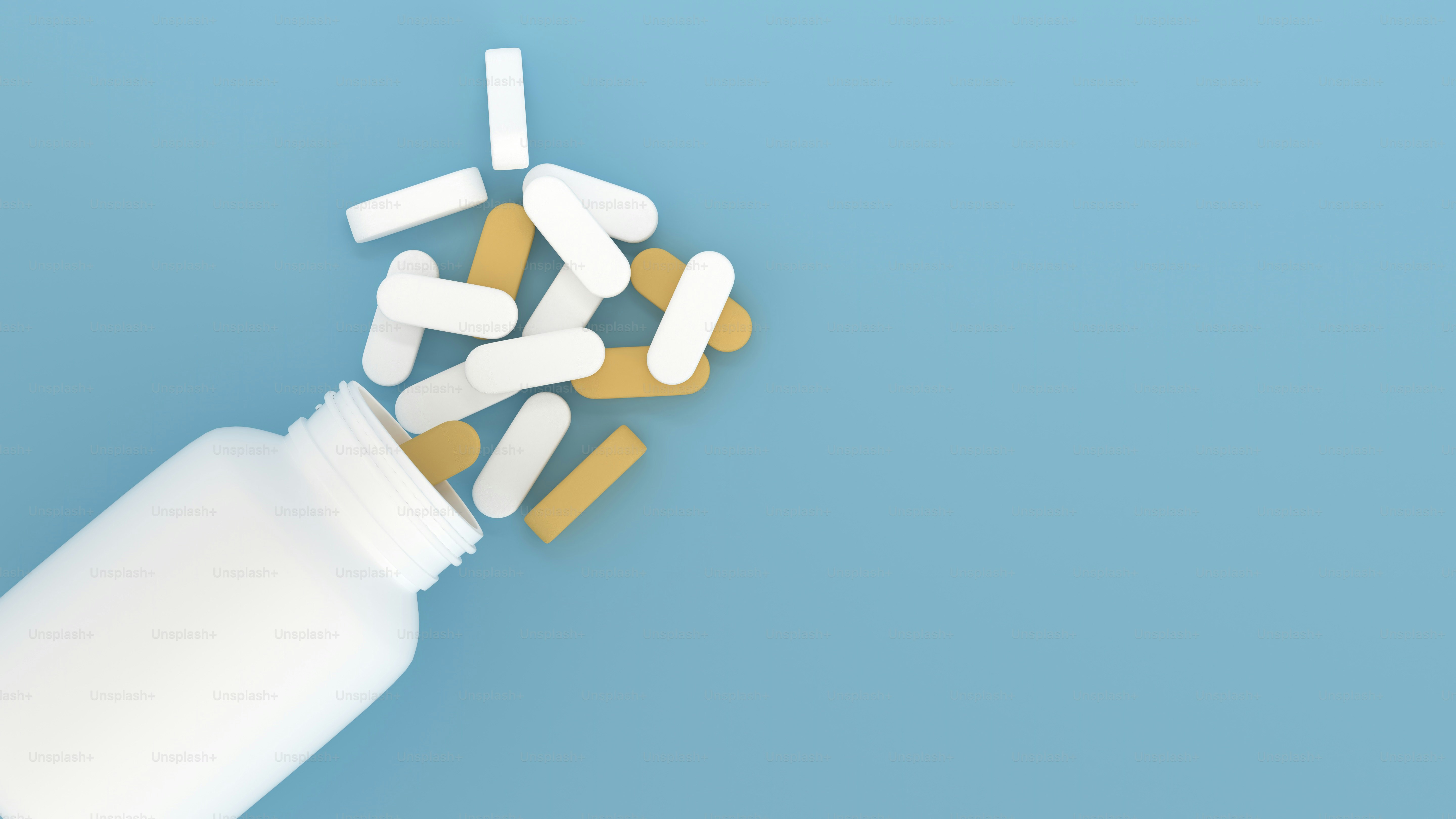 Pills spilling out of a bottle on a blue background photo – Medication ...