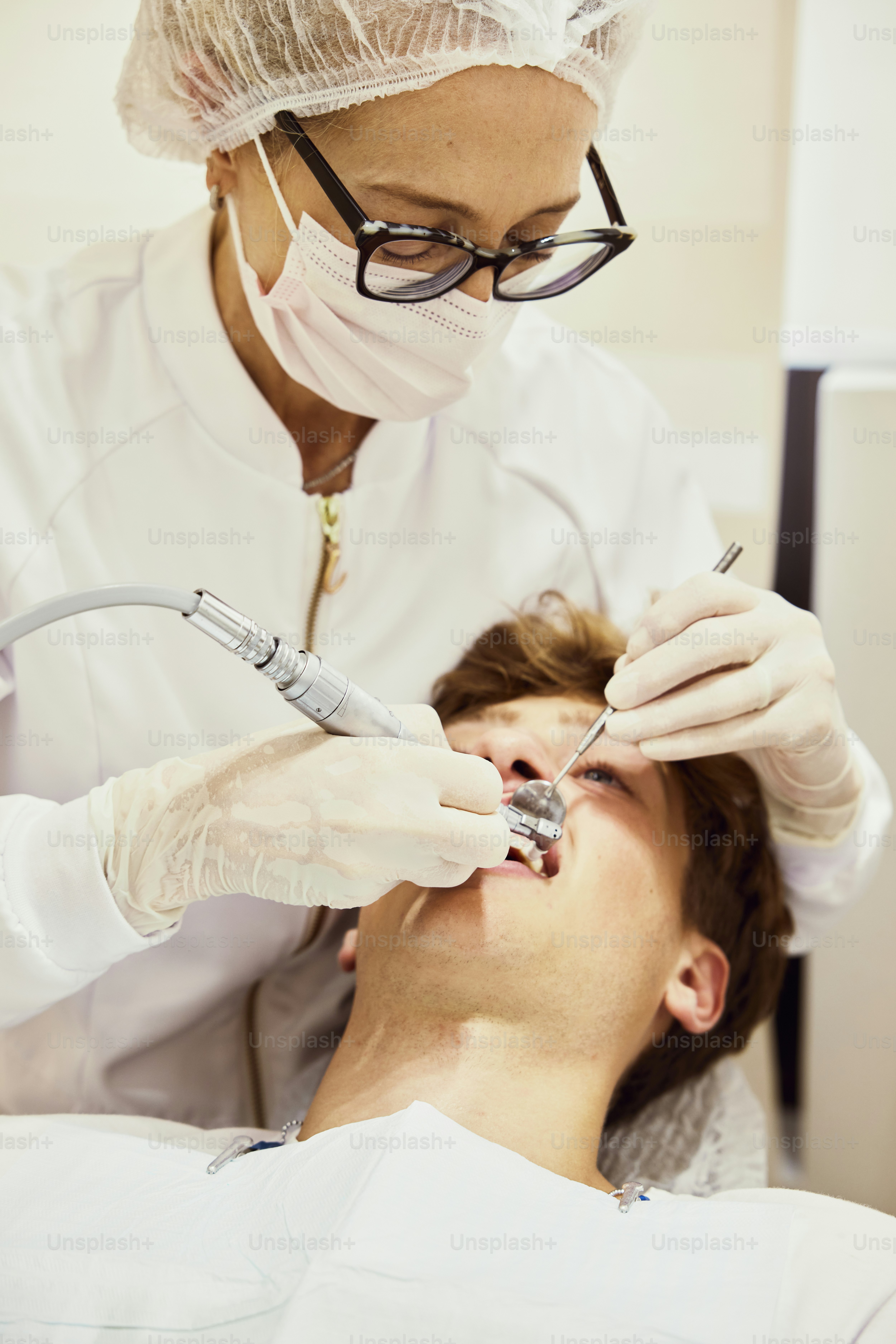 A man getting his teeth checked by a dentist photo – Odontology Image ...