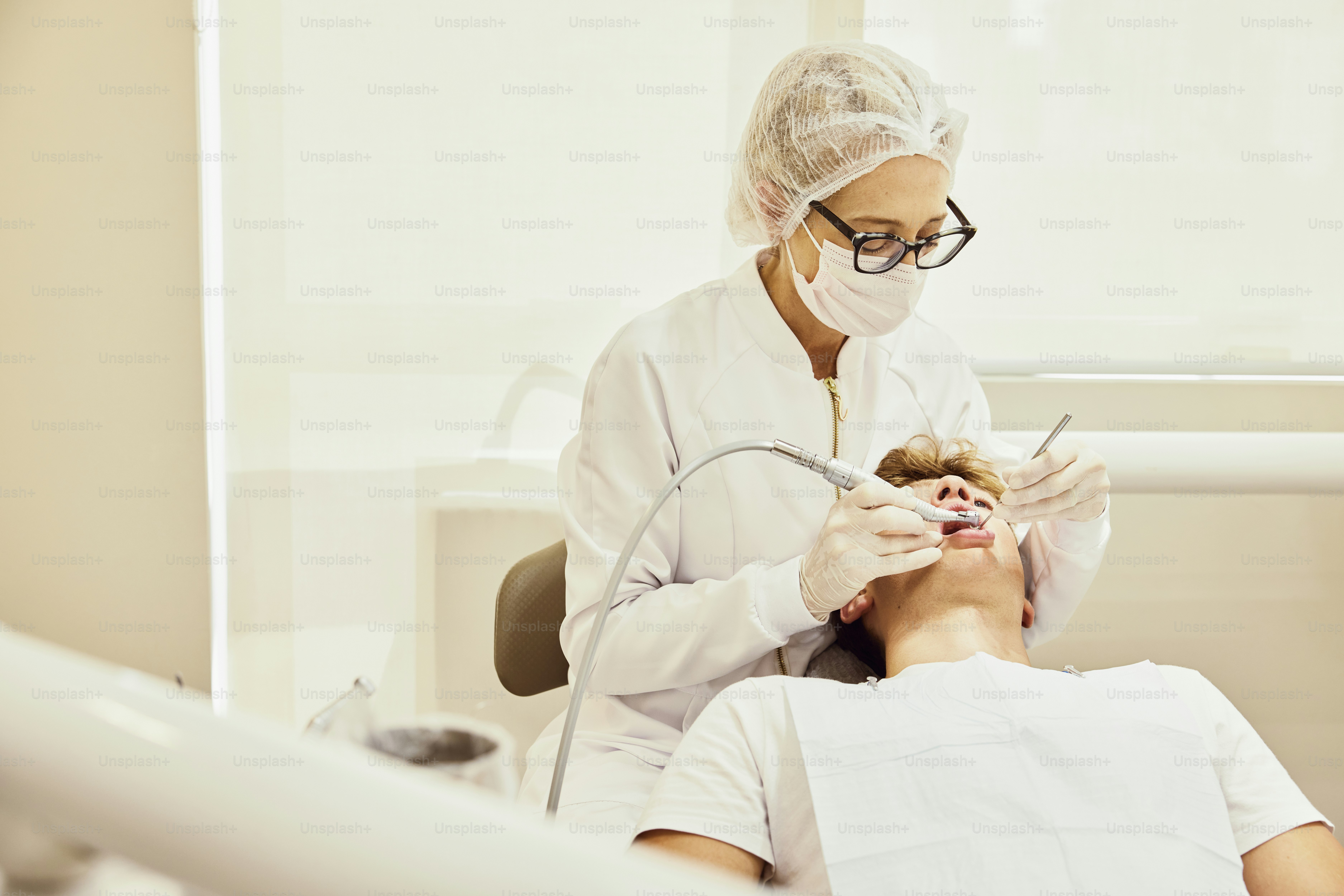 A woman getting her teeth checked by a dentist photo – Odontology Image ...