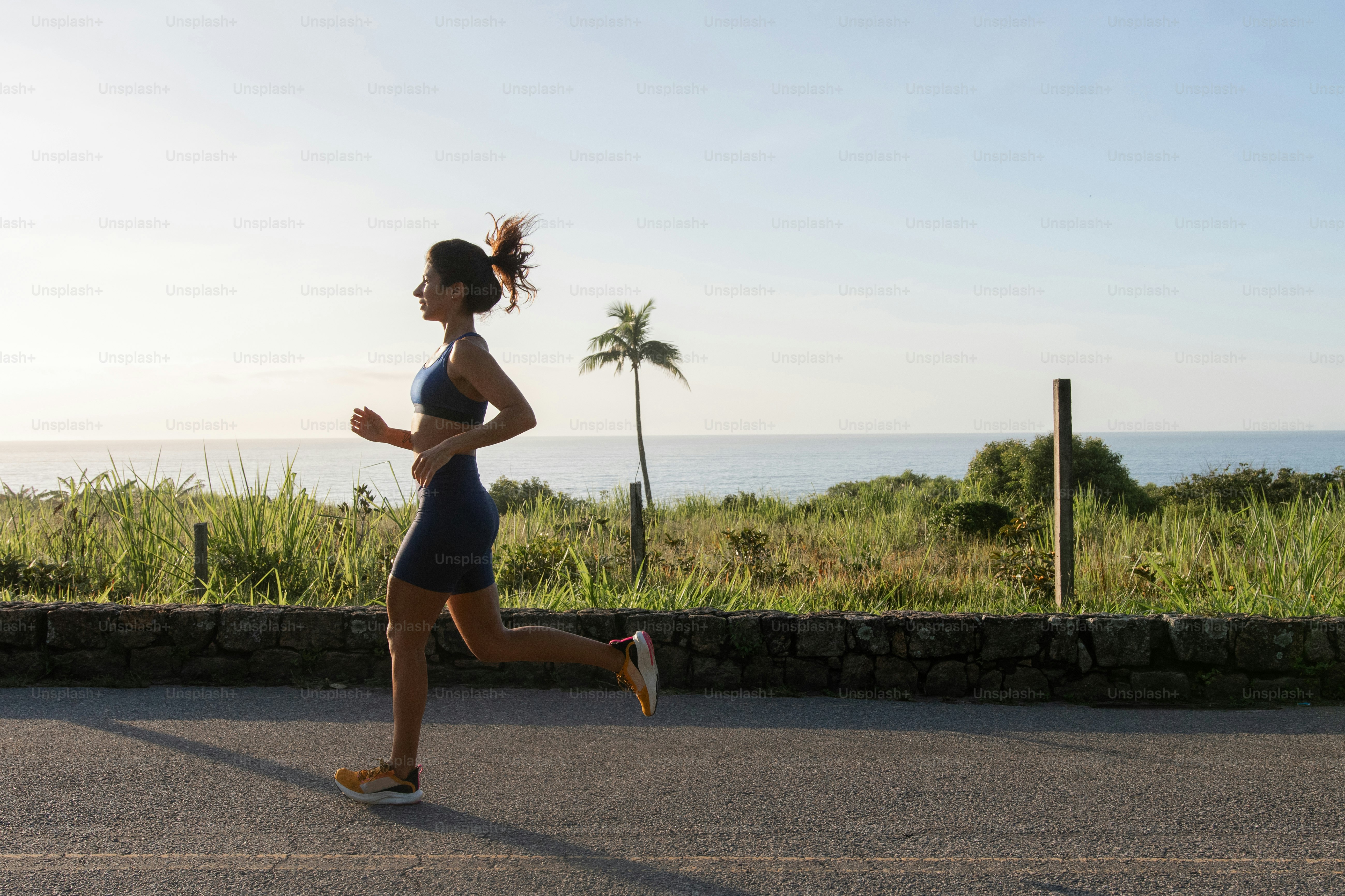 A woman running down a road near the ocean photo – Motivation Image on ...