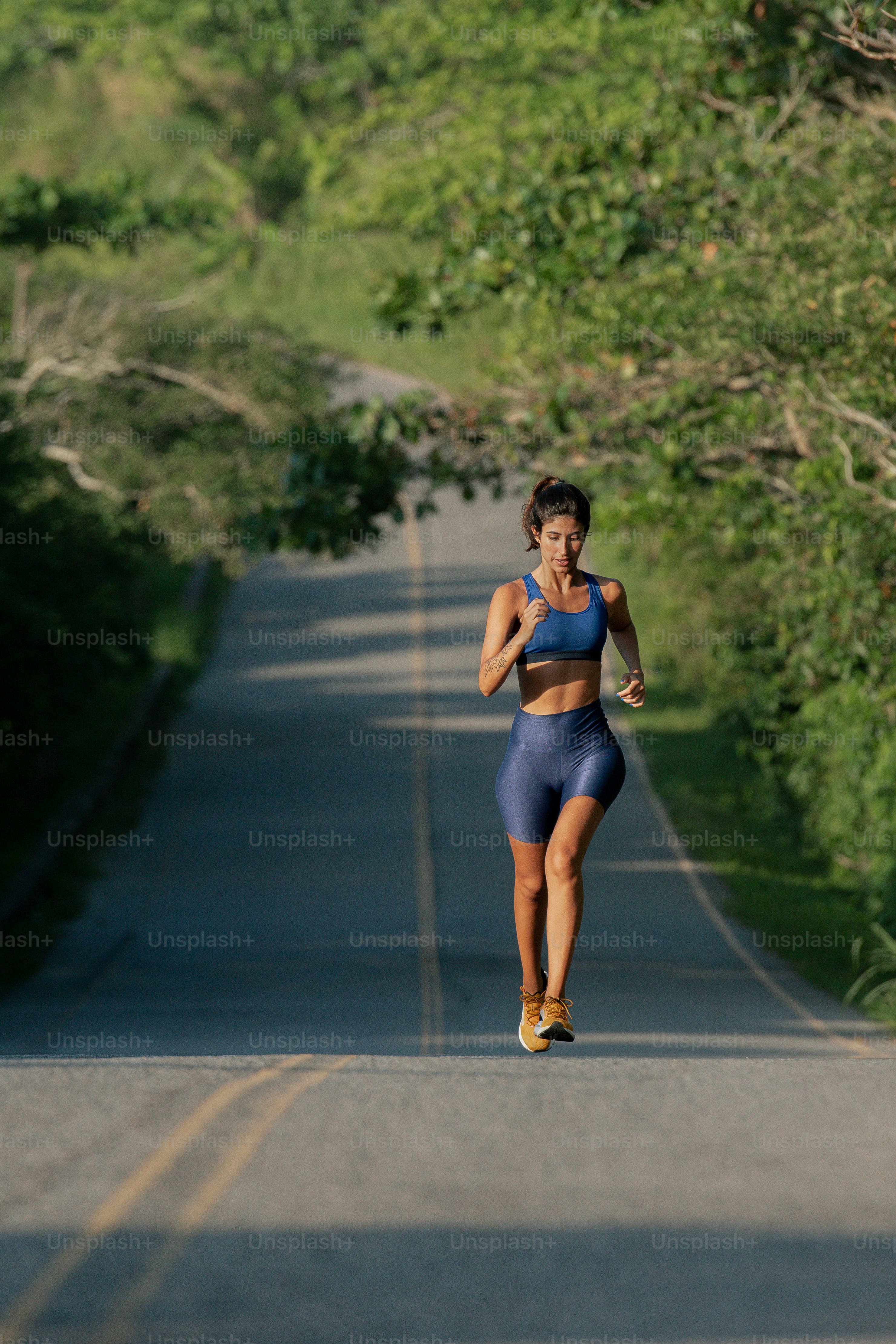 A woman running down a road next to the ocean photo – Running Image on ...