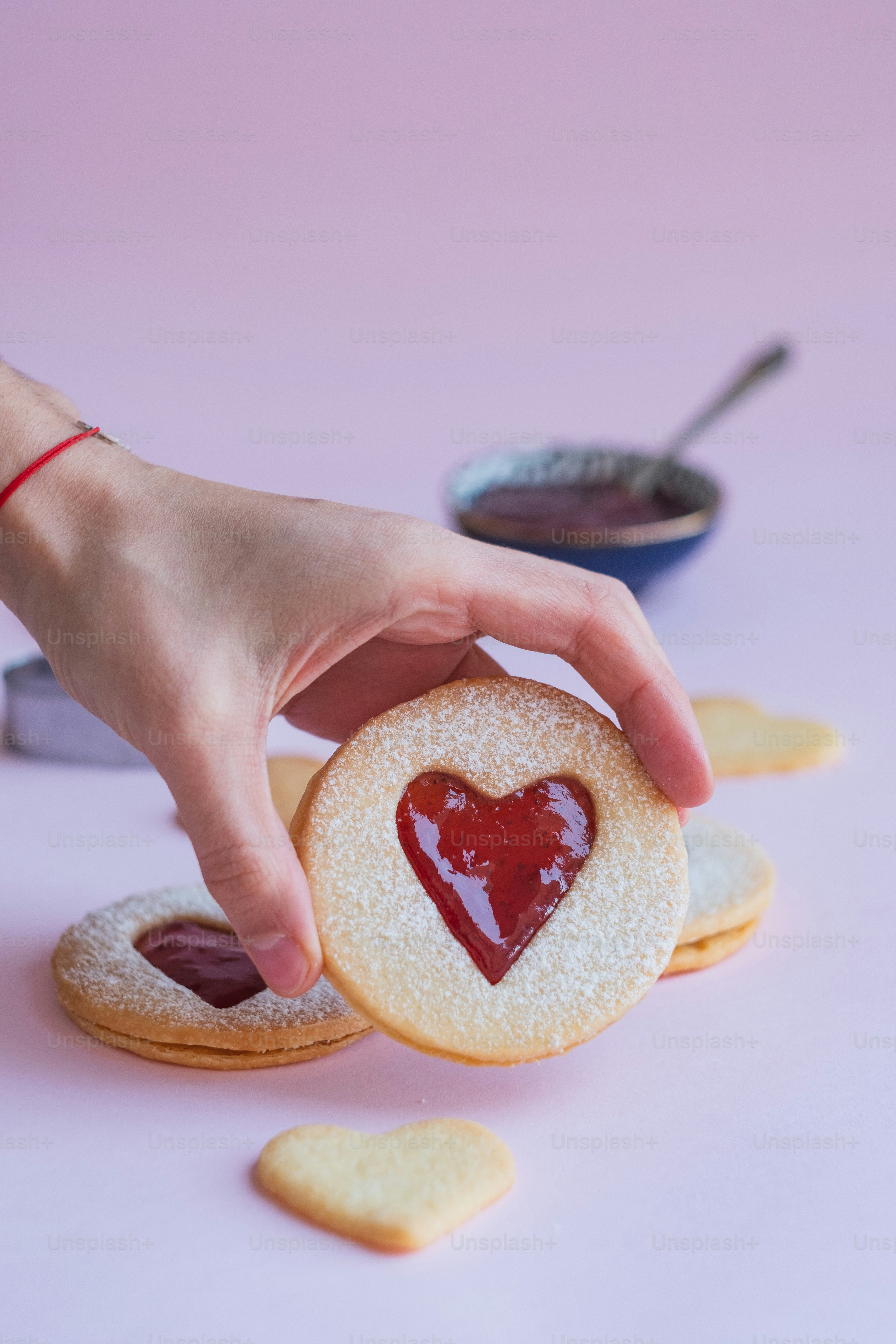 A heart shaped cookie being held by a hand photo – Strawberry jam Image ...