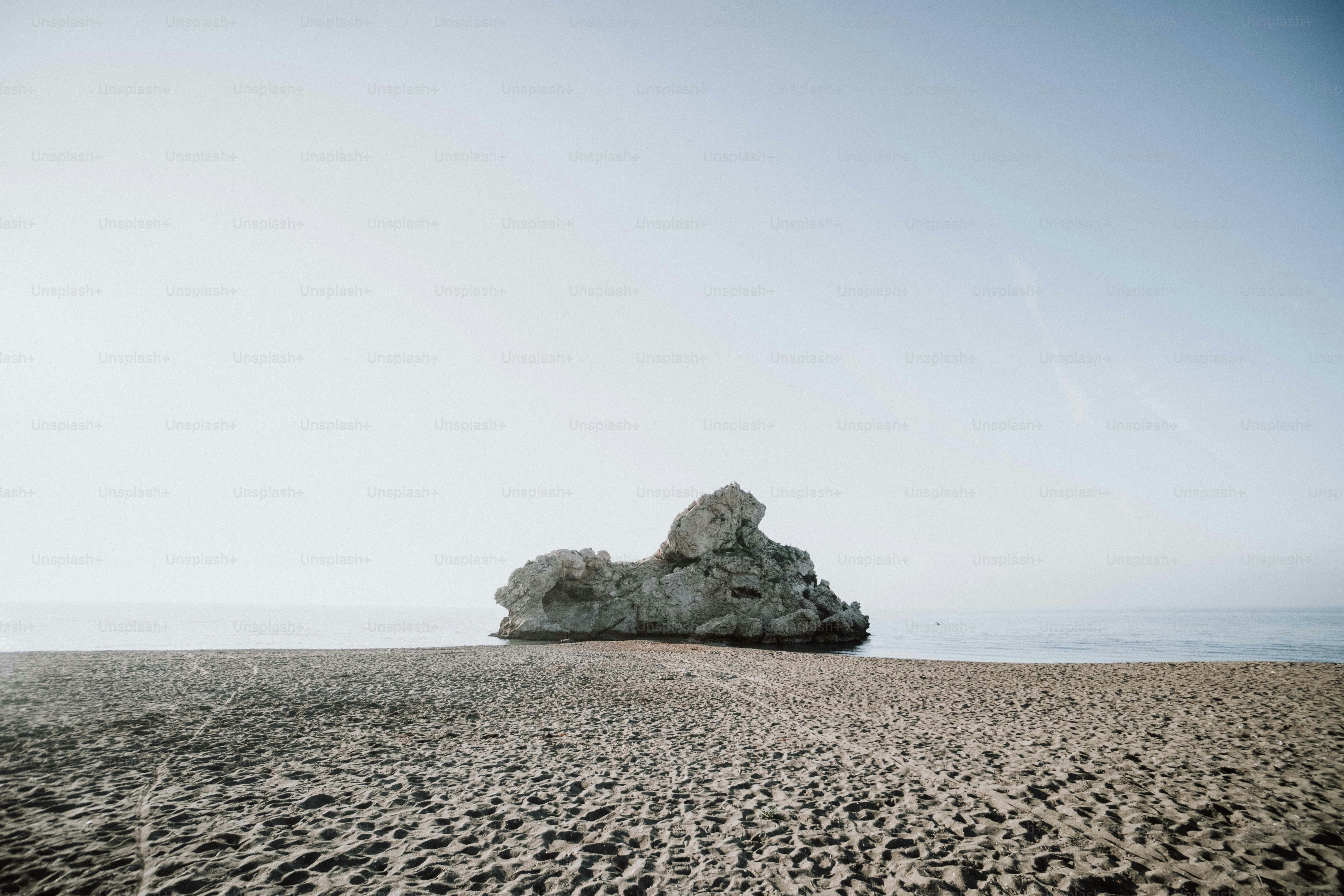 A rock sticking out of the sand on a beach photo – Nature Image on Unsplash