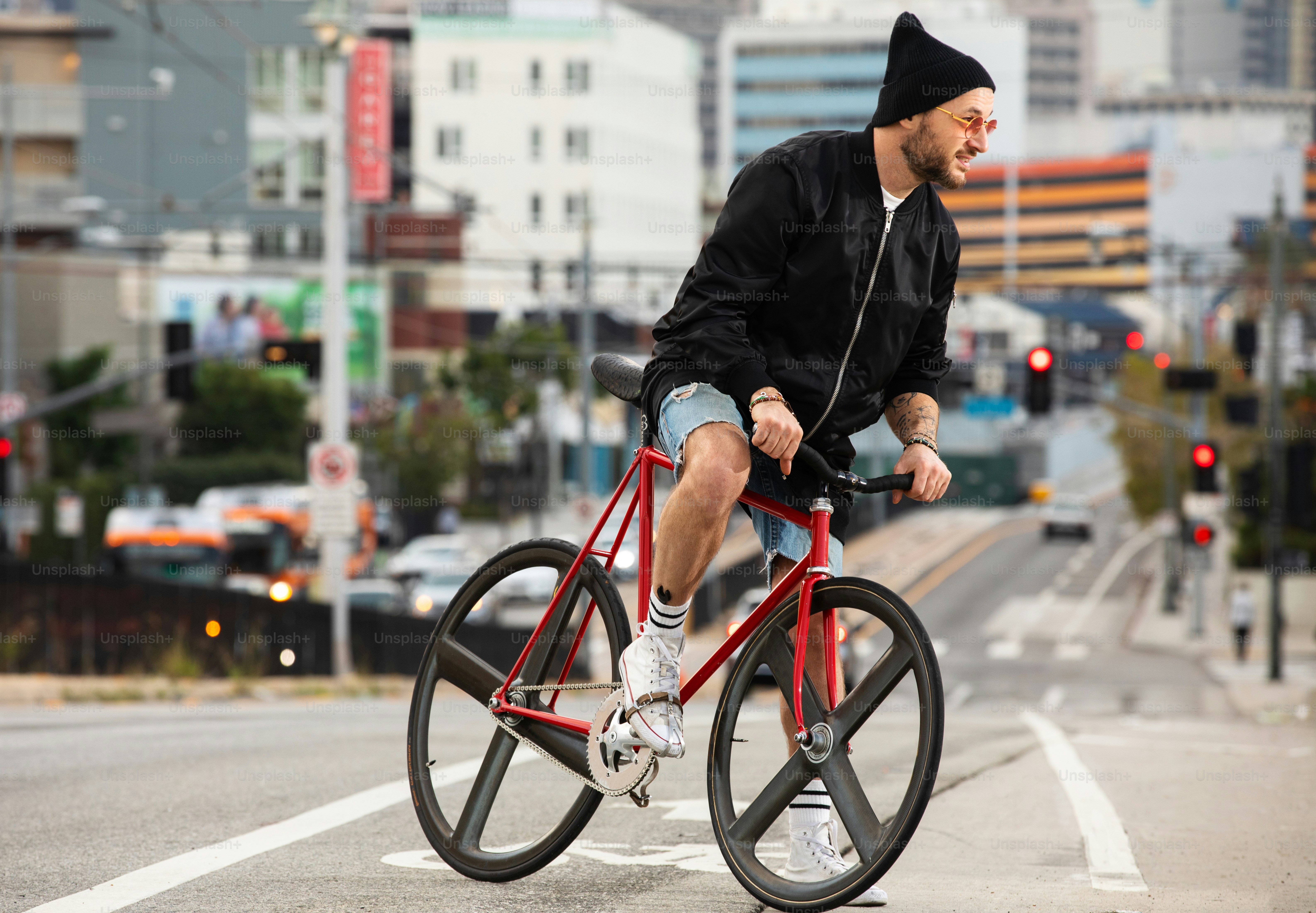 A man riding a red bike down a street photo – Biking Image on Unsplash