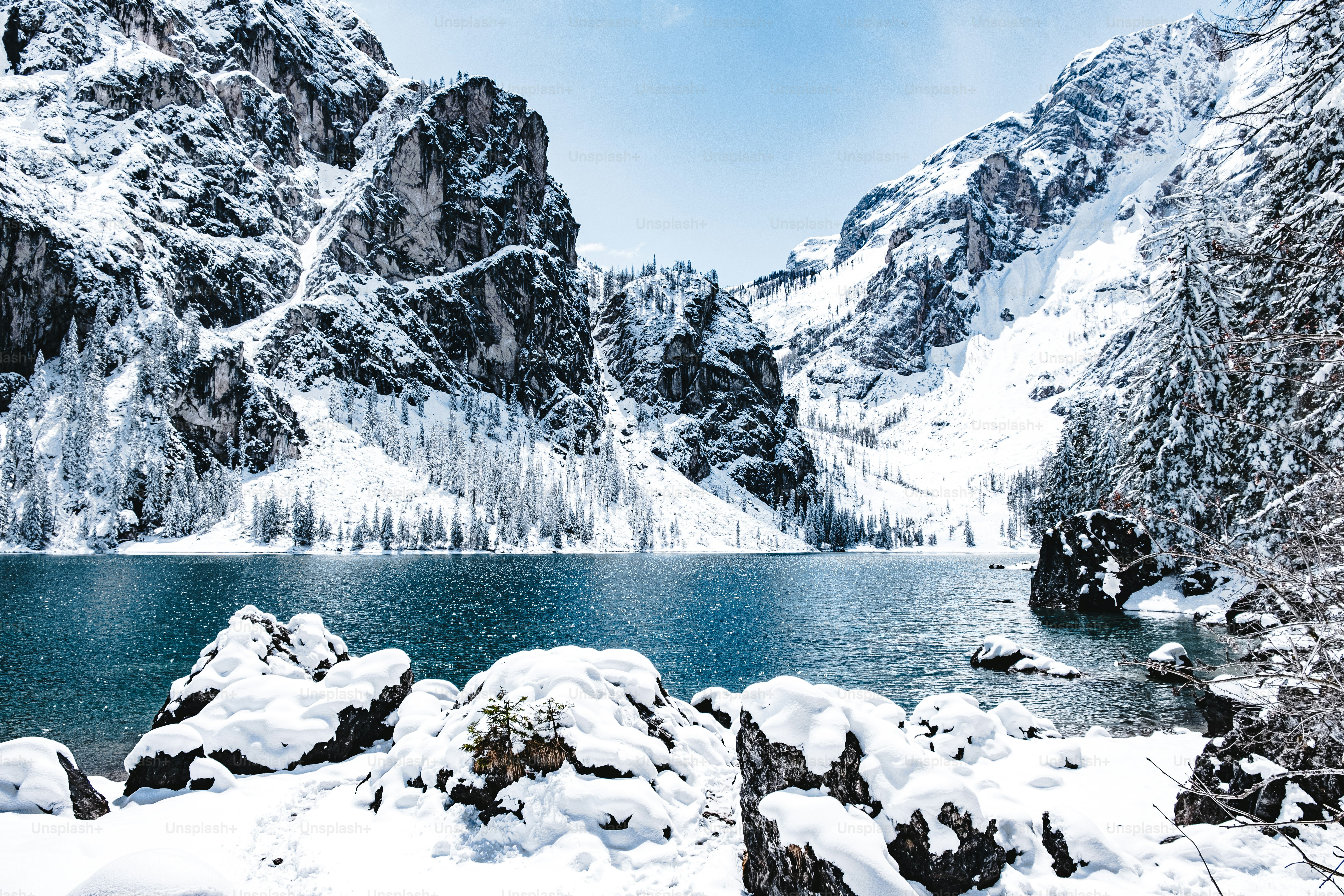 A lake surrounded by mountains covered in snow photo – Winter lake ...