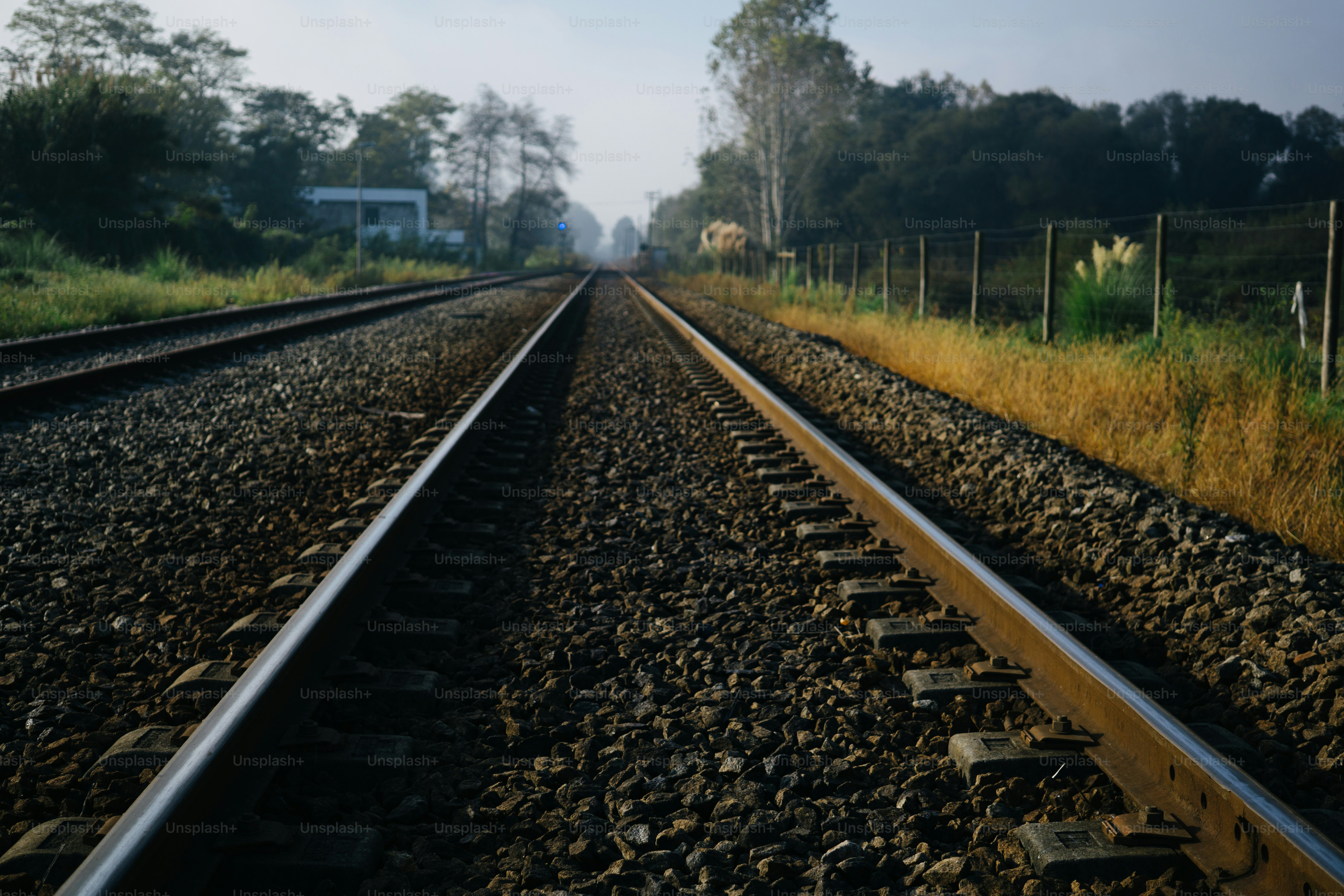 A train track with a wire fence and trees in the background photo ...