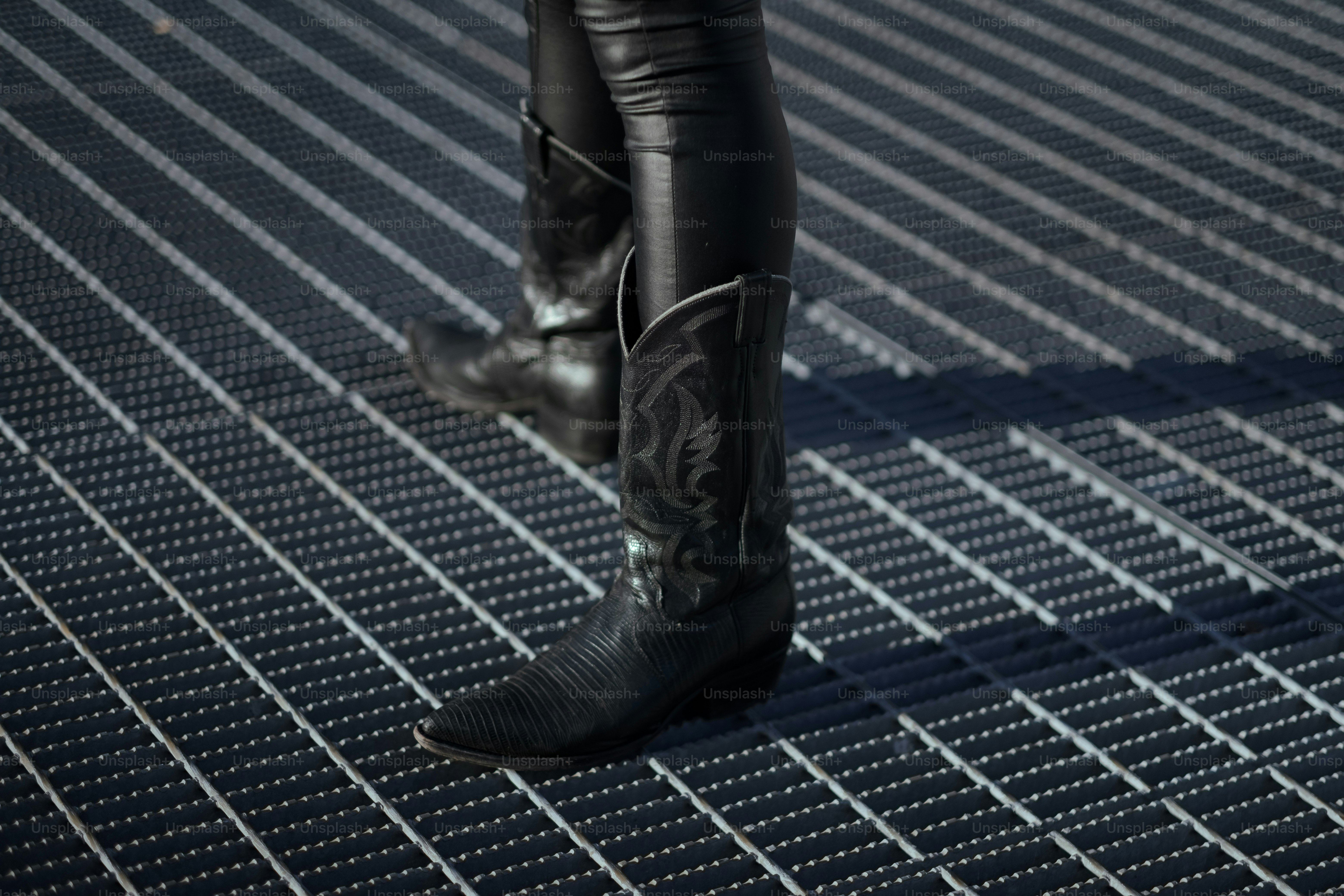 A pair of black cowboy boots on the ground photo – Leather shoes Image ...