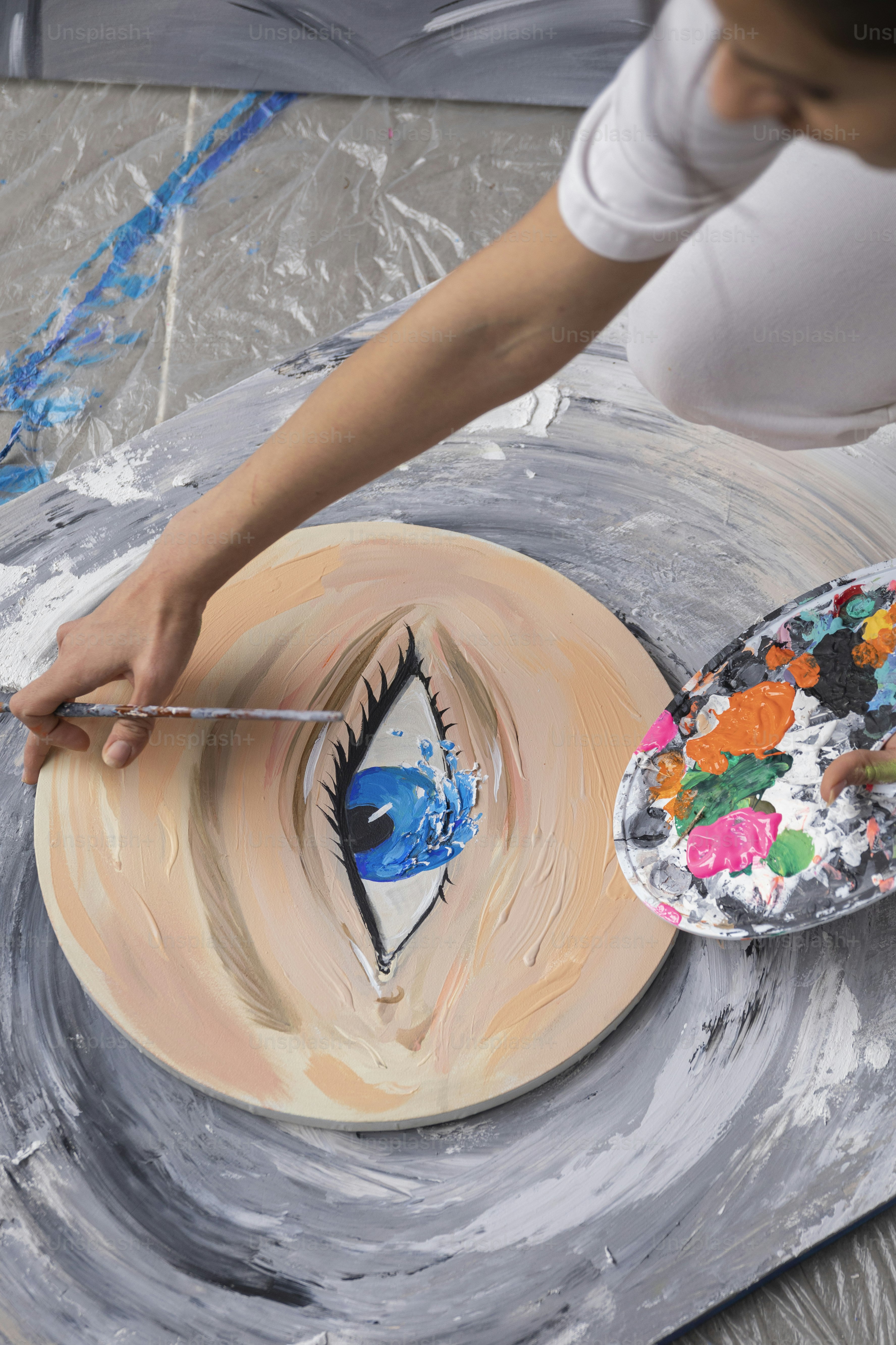 A woman is painting a picture on a plate photo – Paint palette Image on ...