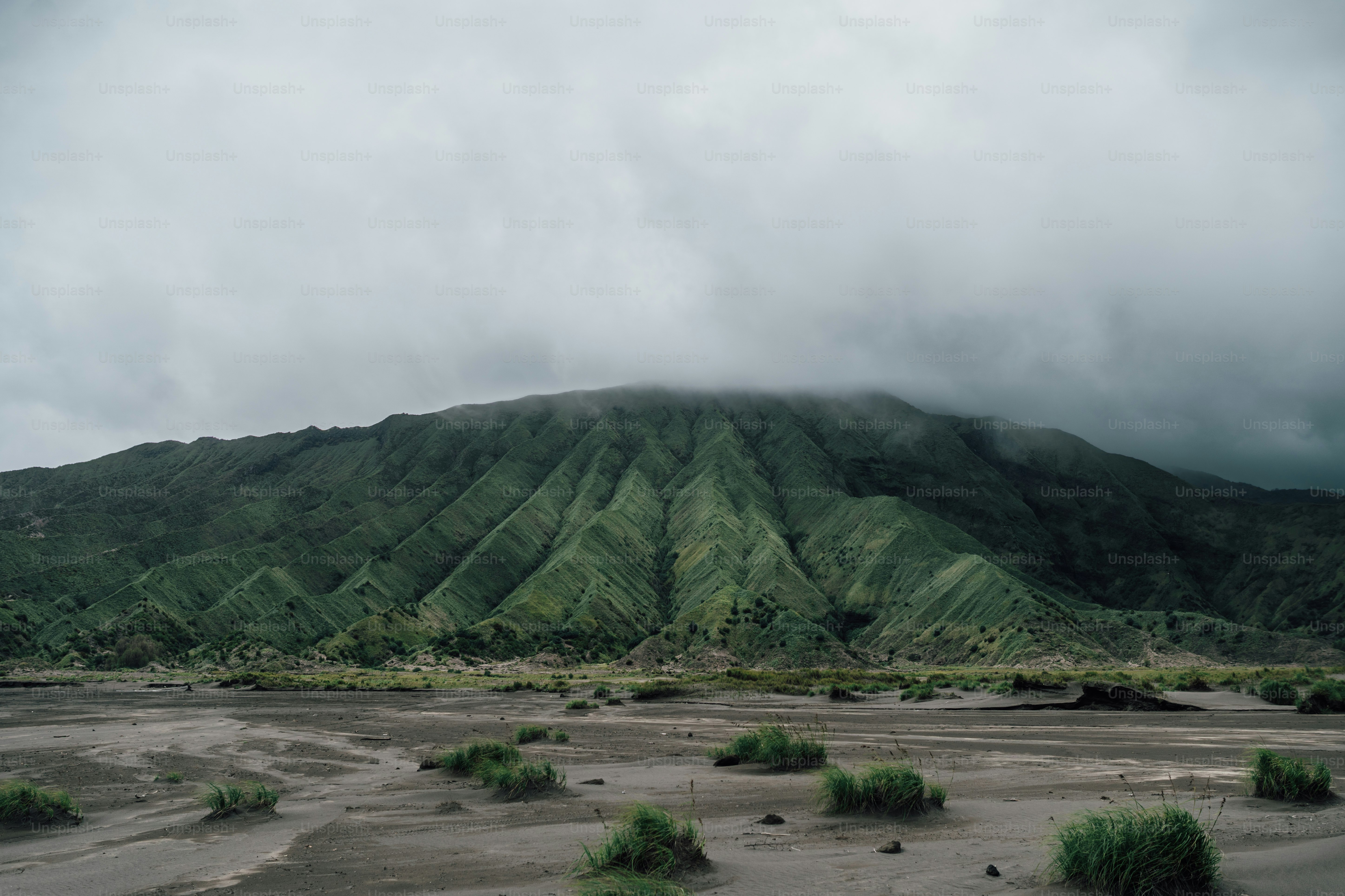 A large green mountain covered in clouds in the distance photo – Travel ...