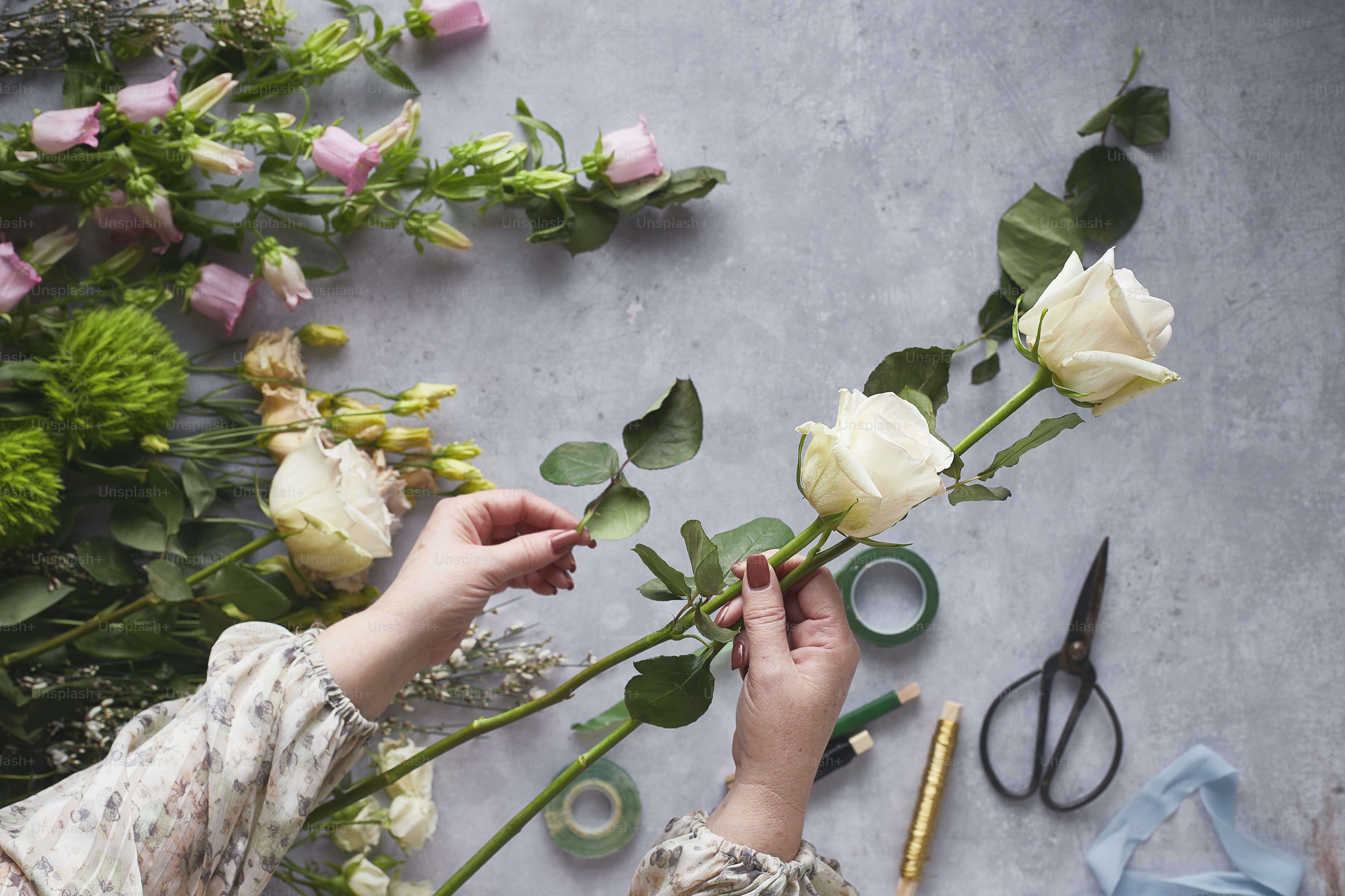 A person cutting up flowers with scissors on a table photo – Flowers ...