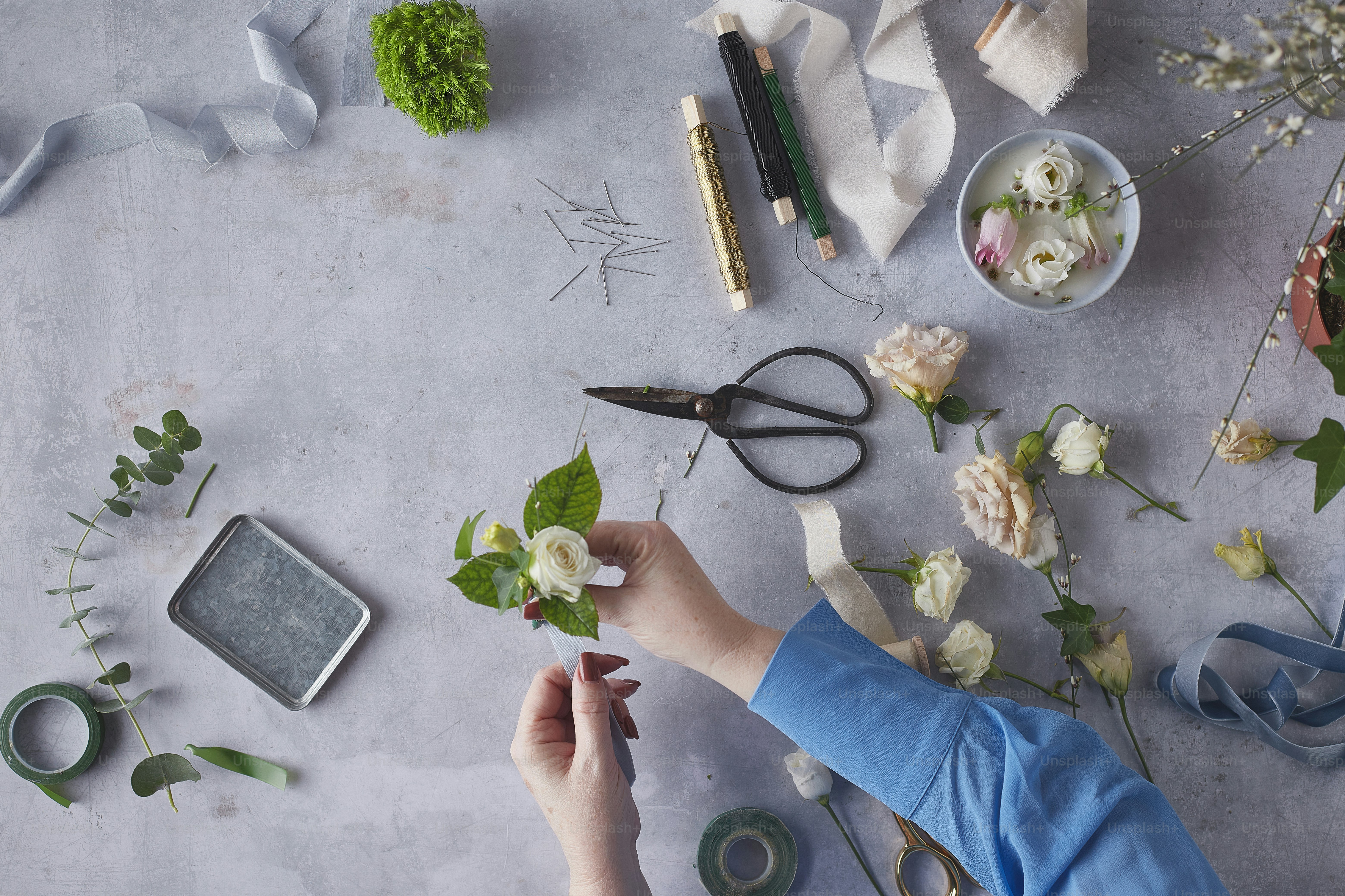A person cutting up flowers with scissors on a table photo – Wedding ...