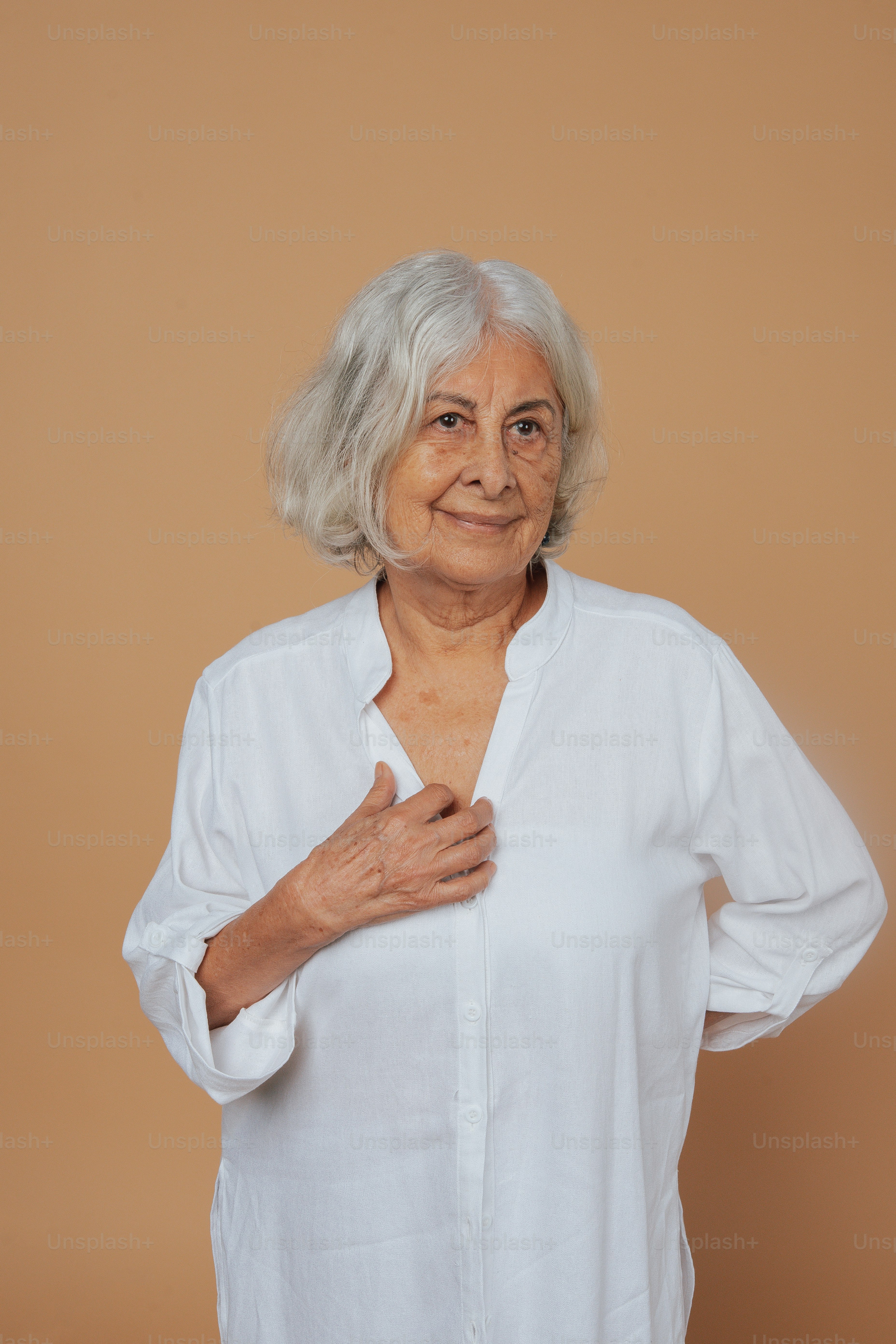 An older woman posing for a picture with her hands on her chest photo ...