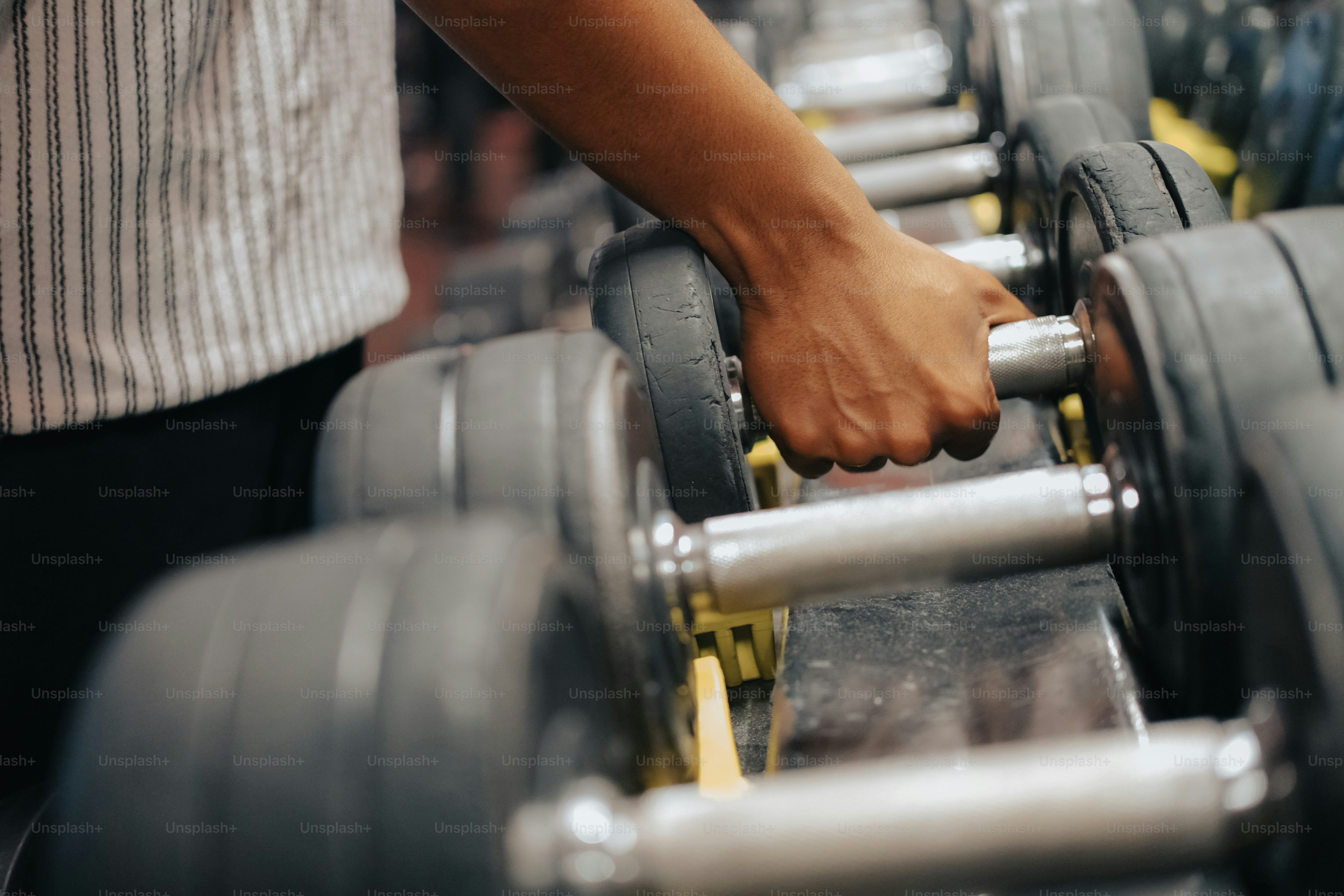 A person holding a dumbbell in a gym photo – Gym weights Image on Unsplash