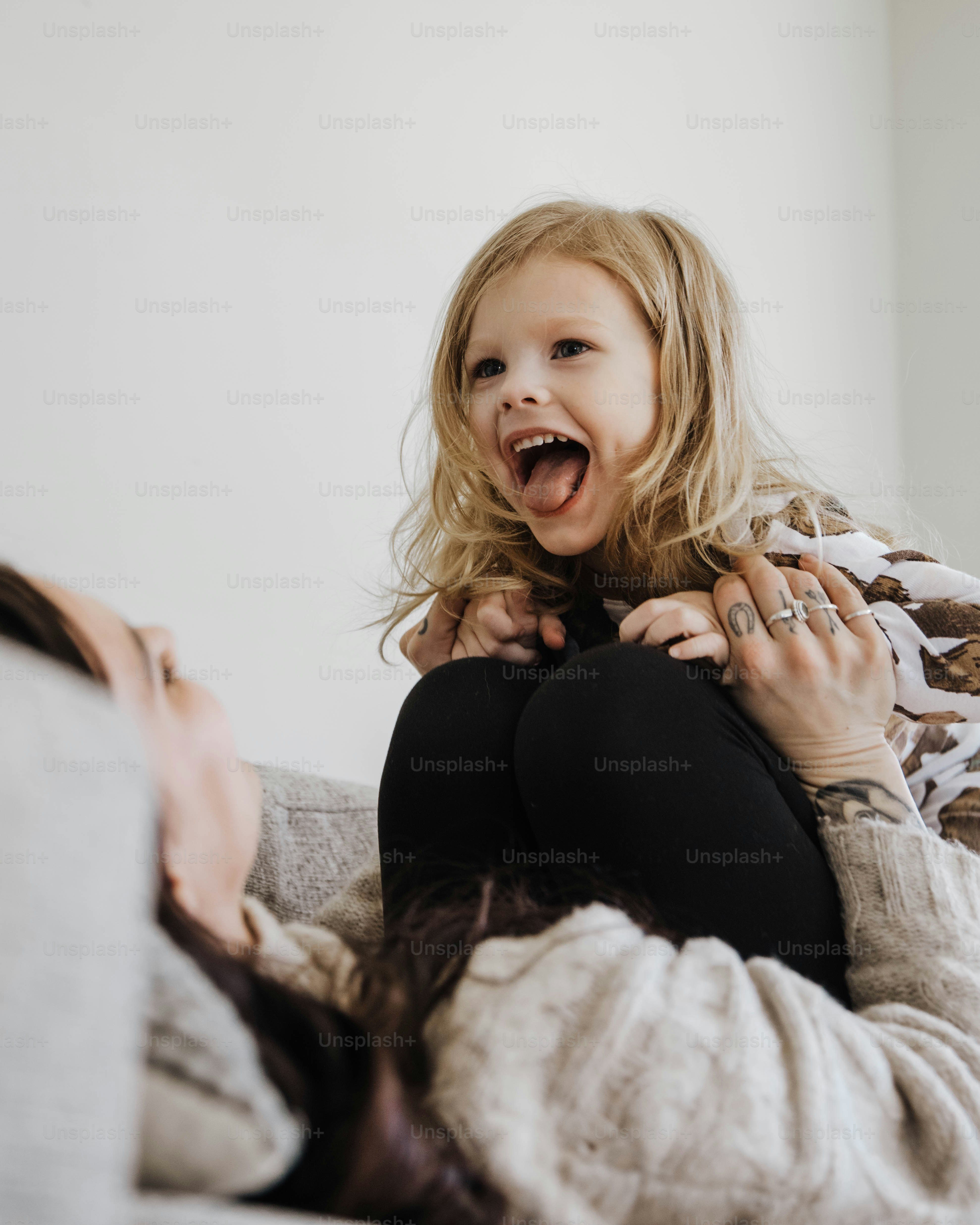 Foto Una niña sentada encima de un sofá con la boca abierta – Madre ...