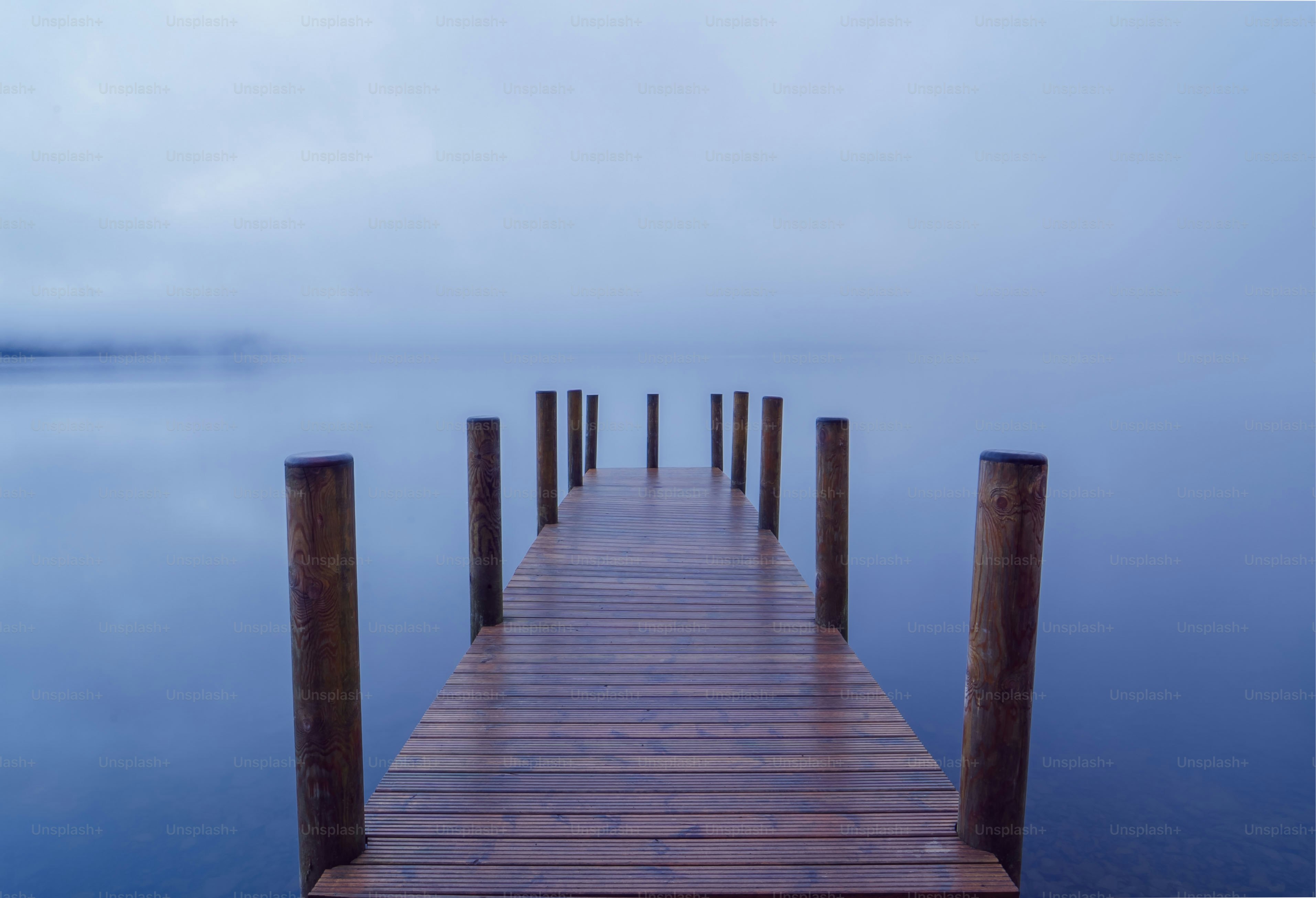 A dock on a lake at sunset with mountains in the background photo ...