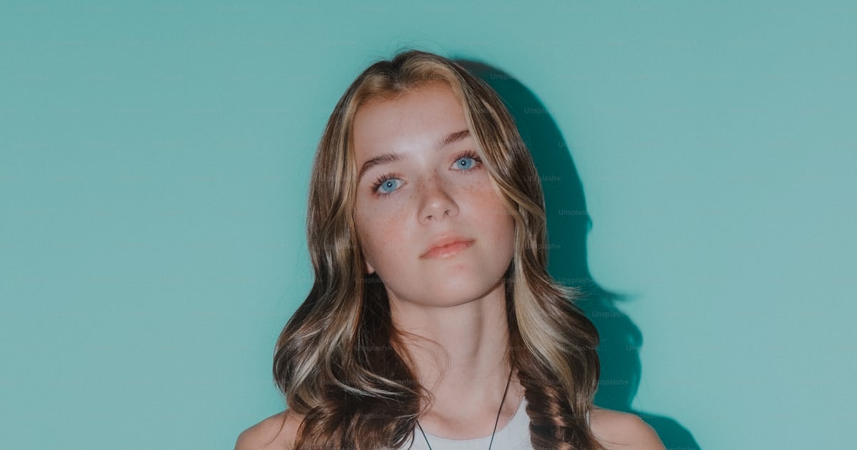 Una Mujer Parada Frente A Una Pared Azul Foto Imagen De Mujer Joven