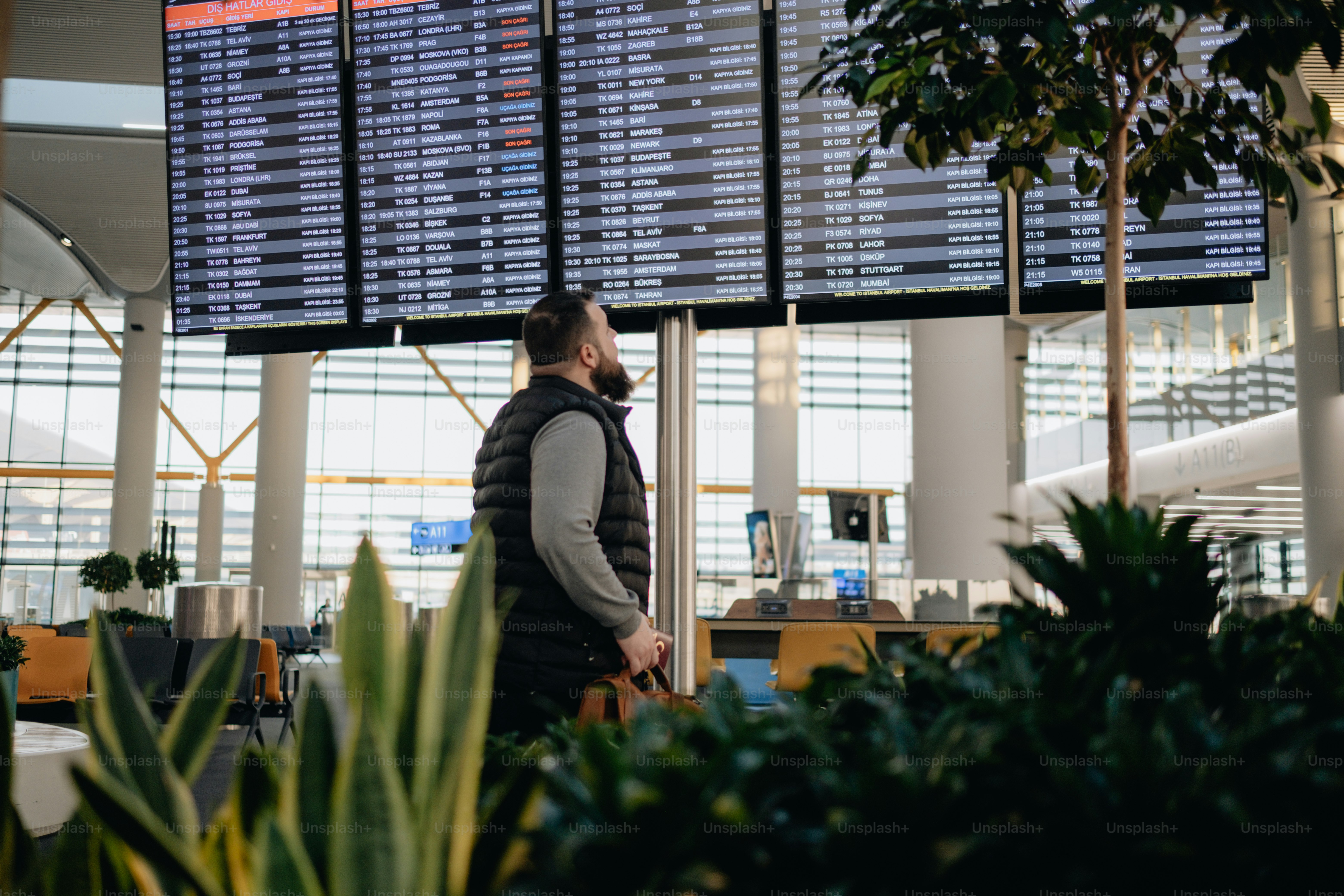 A man standing in front of a large screen in an airport photo ...
