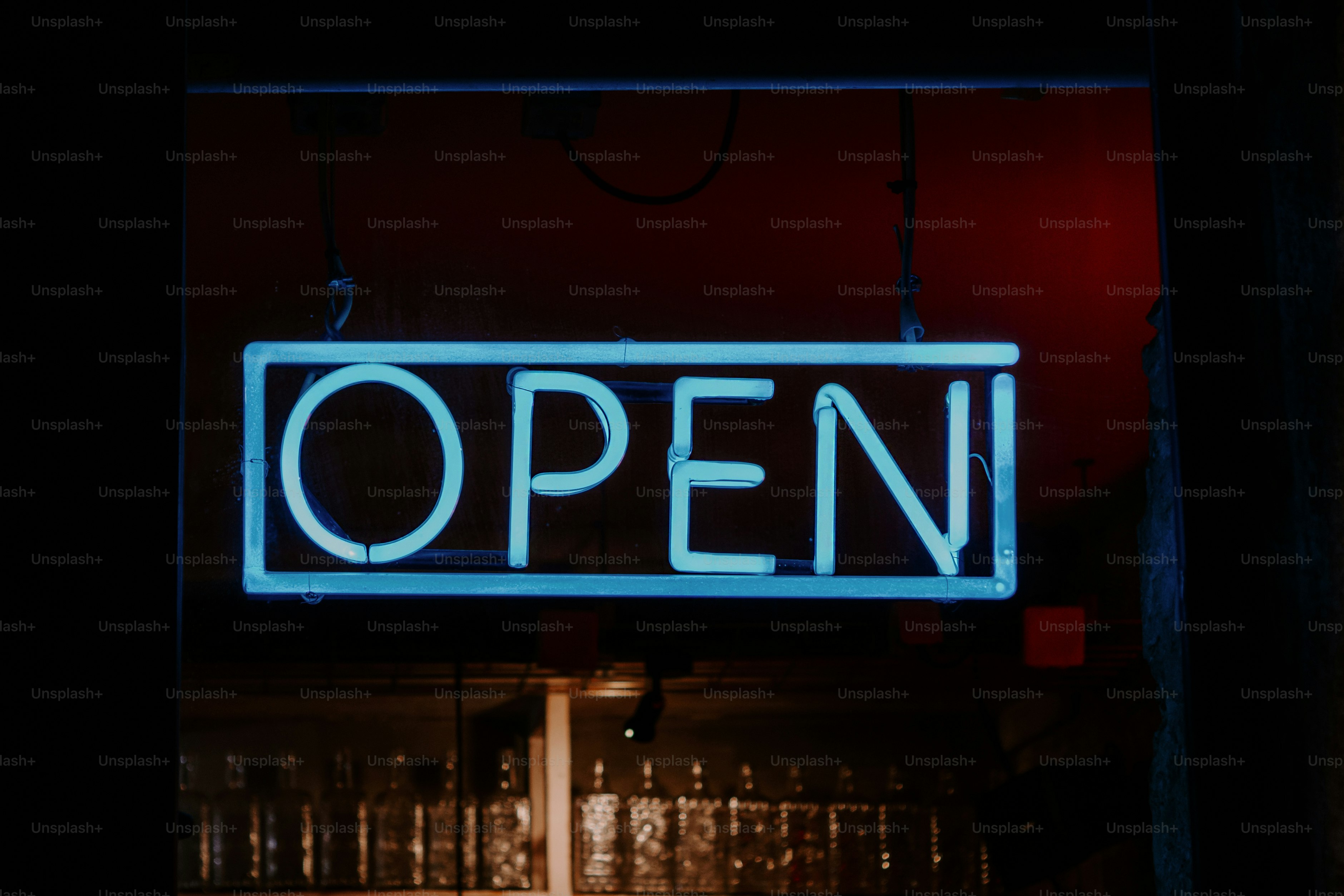 A neon open sign hanging from the side of a building photo – Blue neon ...
