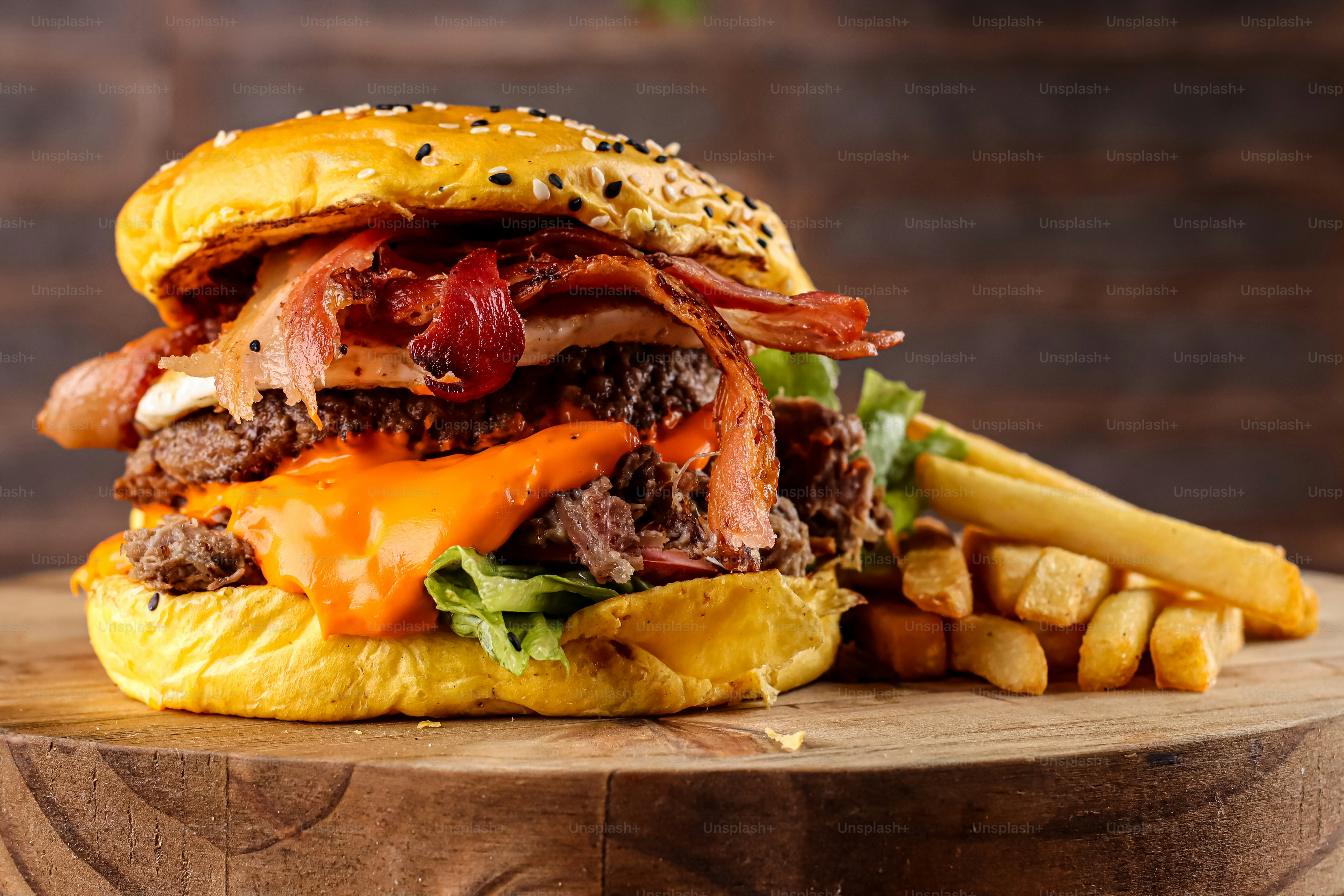 A bacon cheeseburger with fries on a wooden table photo – Burger and ...
