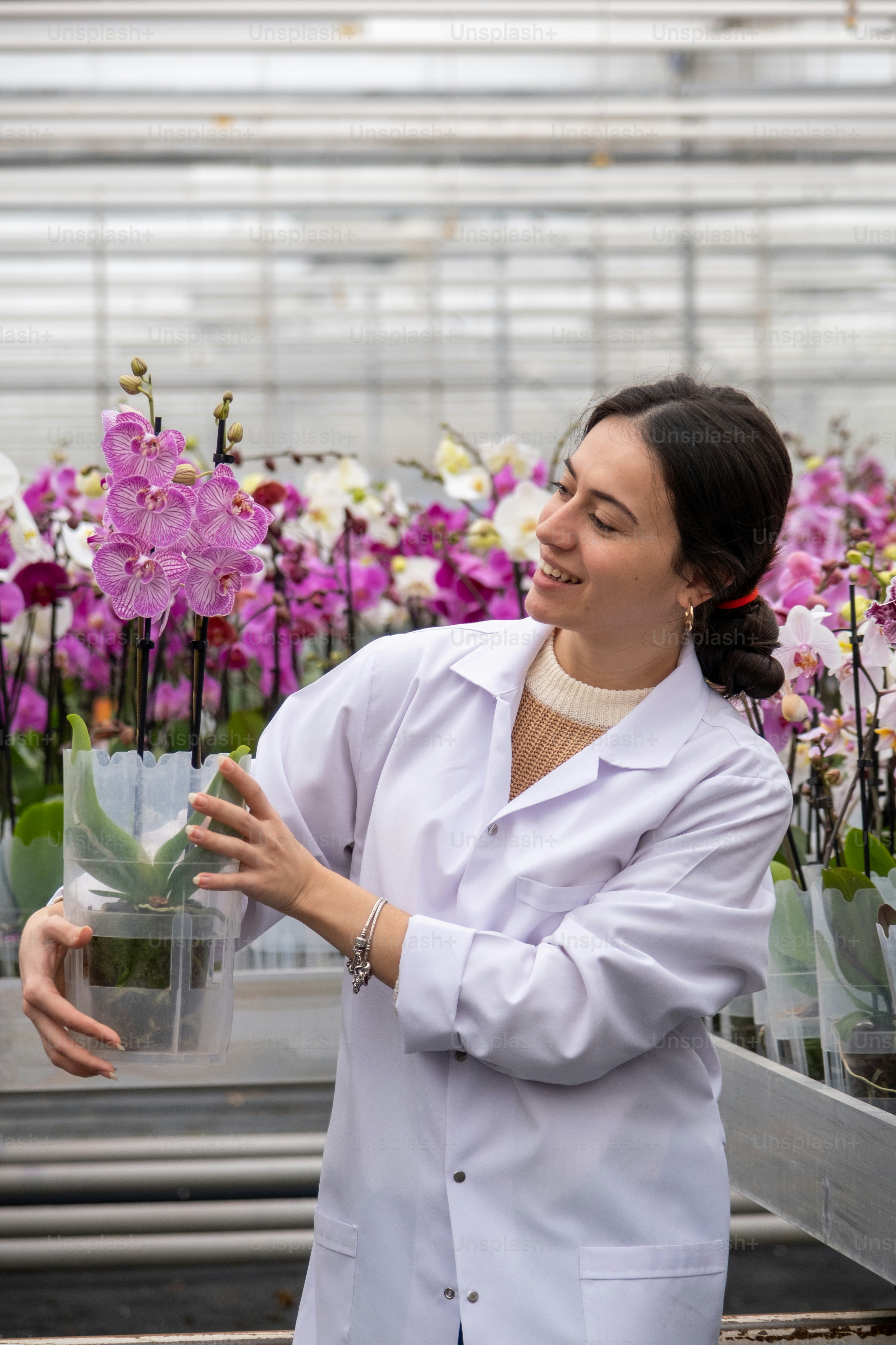 A woman in a white lab coat holding a potted plant photo – Pots Image ...