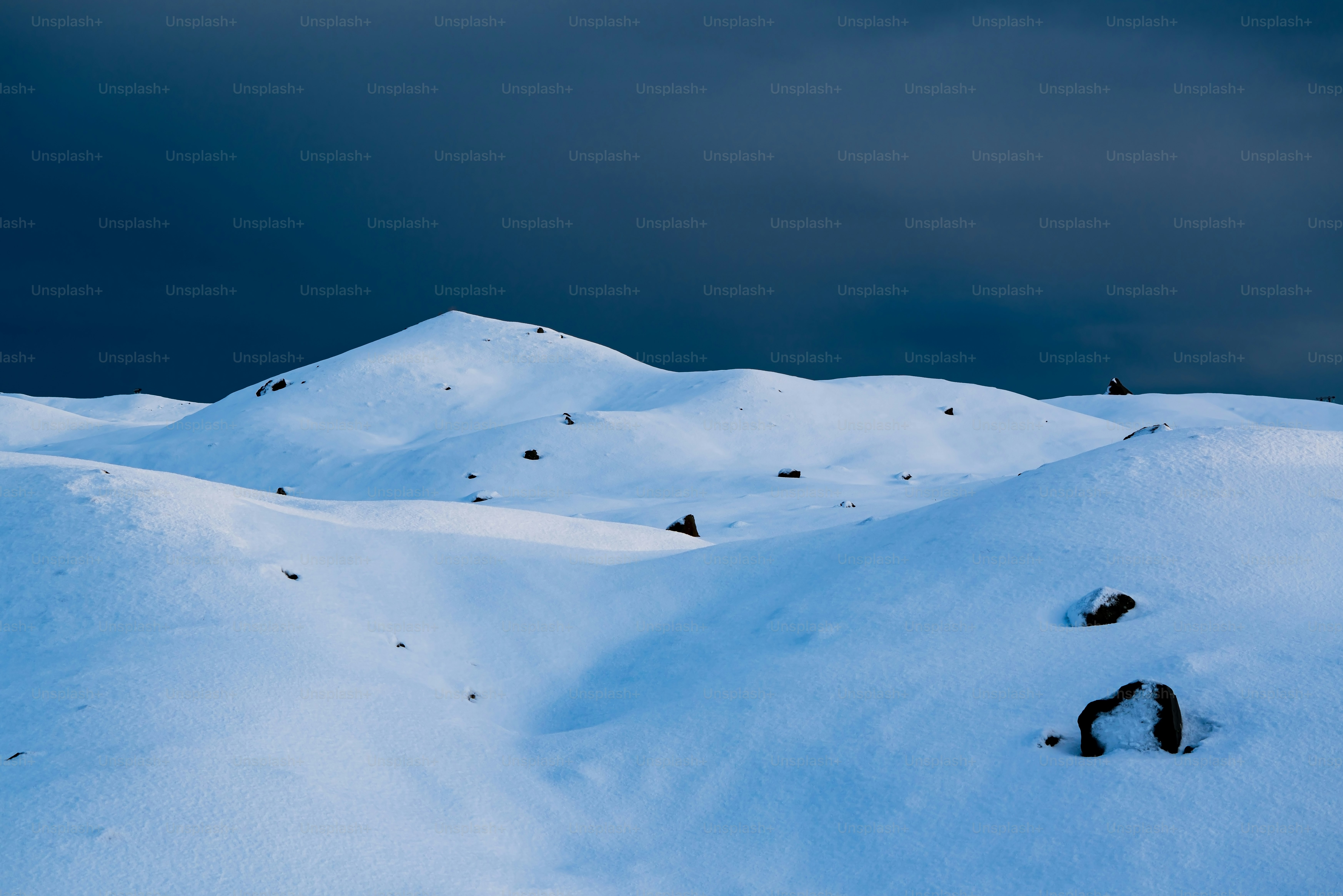A group of snow covered hills under a cloudy sky photo – Outdoors Image ...