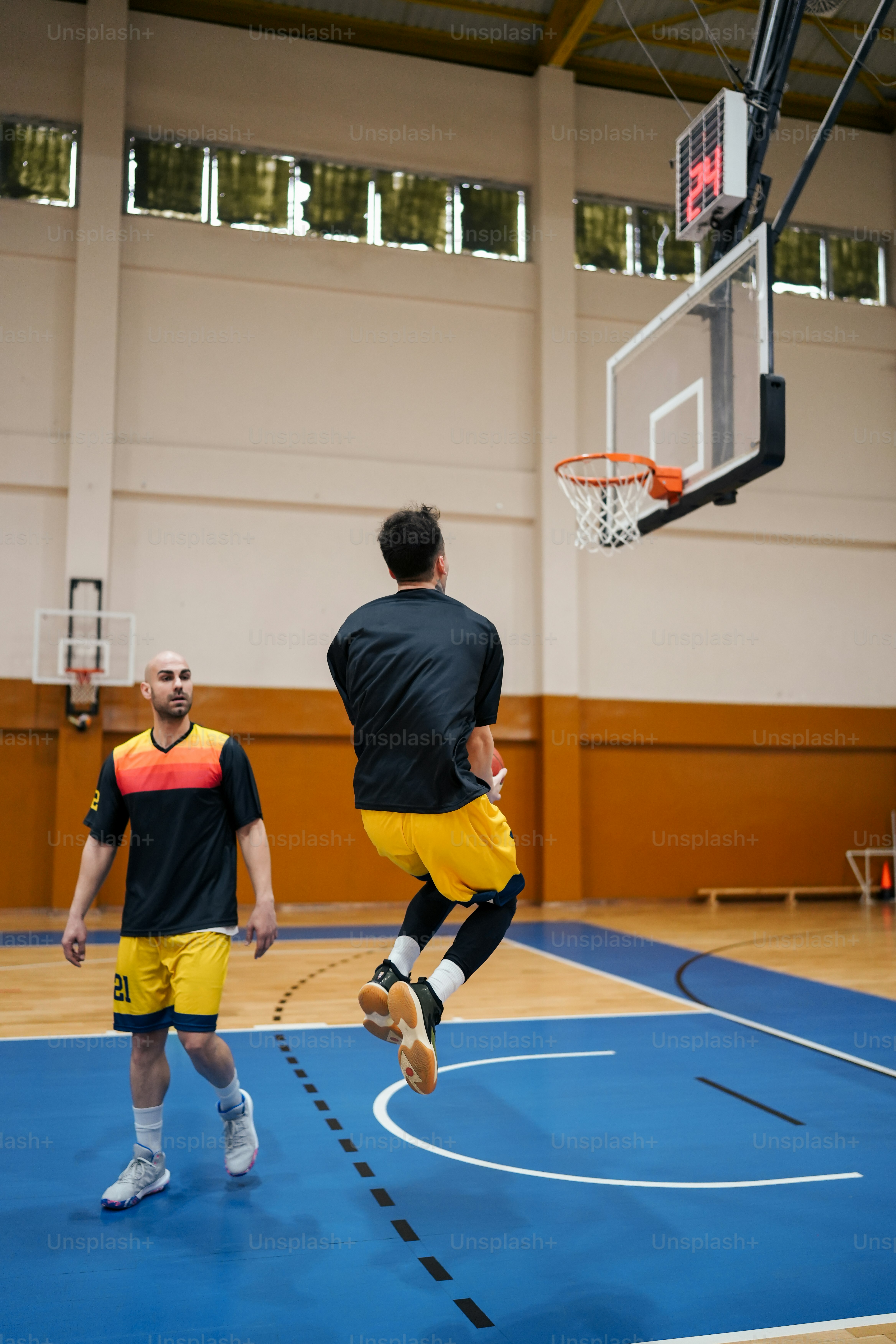 A couple of men standing on top of a basketball court photo ...