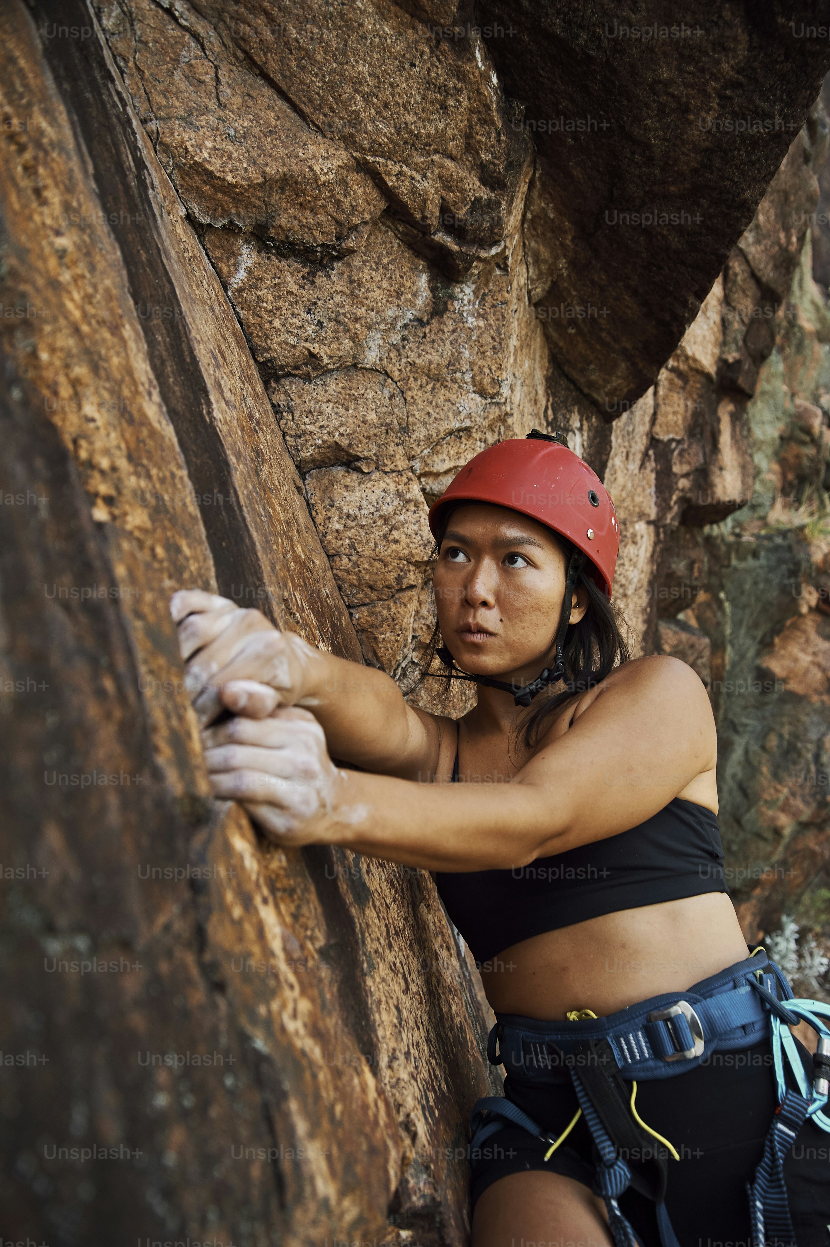 A woman climbing up the side of a mountain photo – Climbing Image on ...