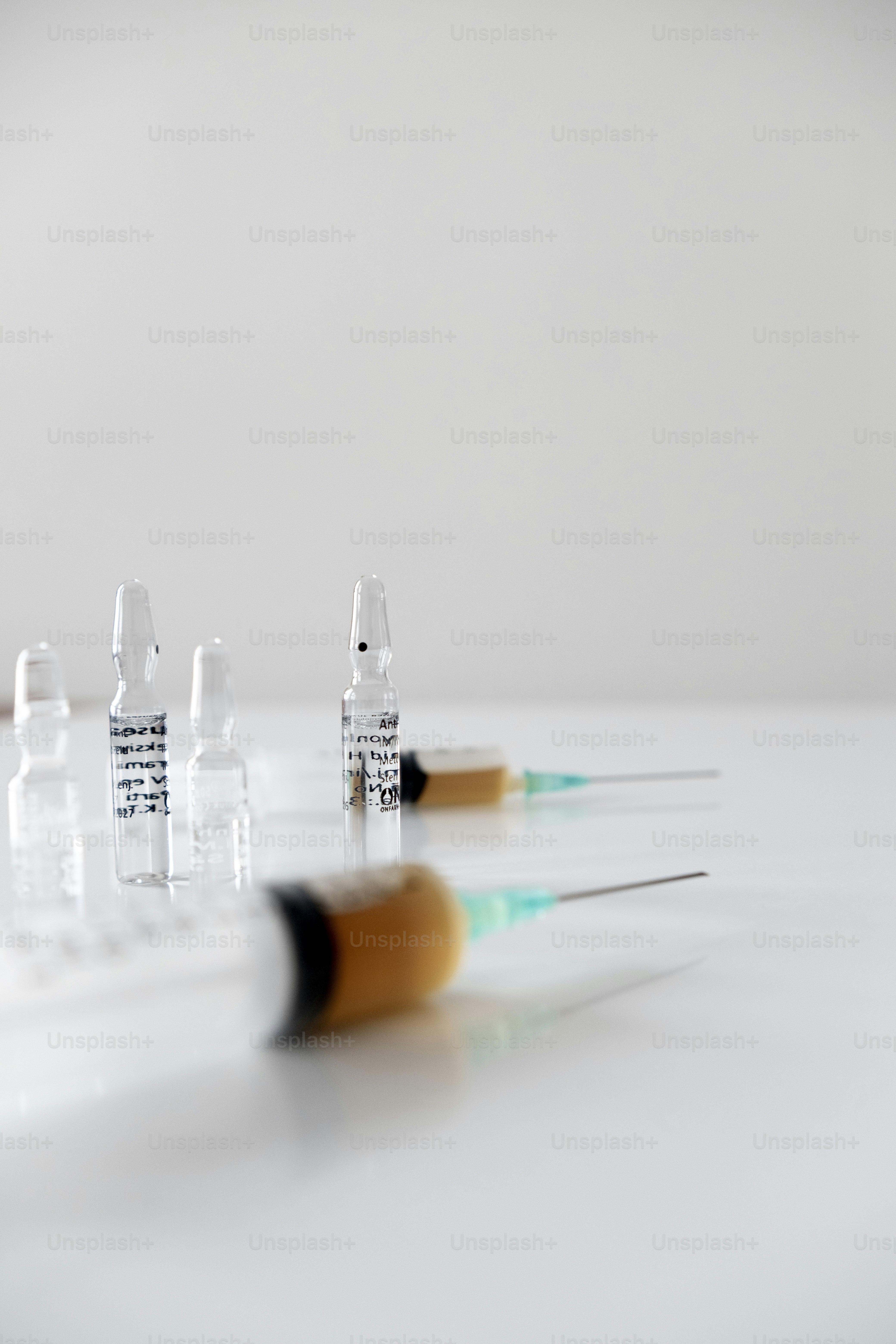 A row of syrings sitting on top of a white table photo – Disease Image ...