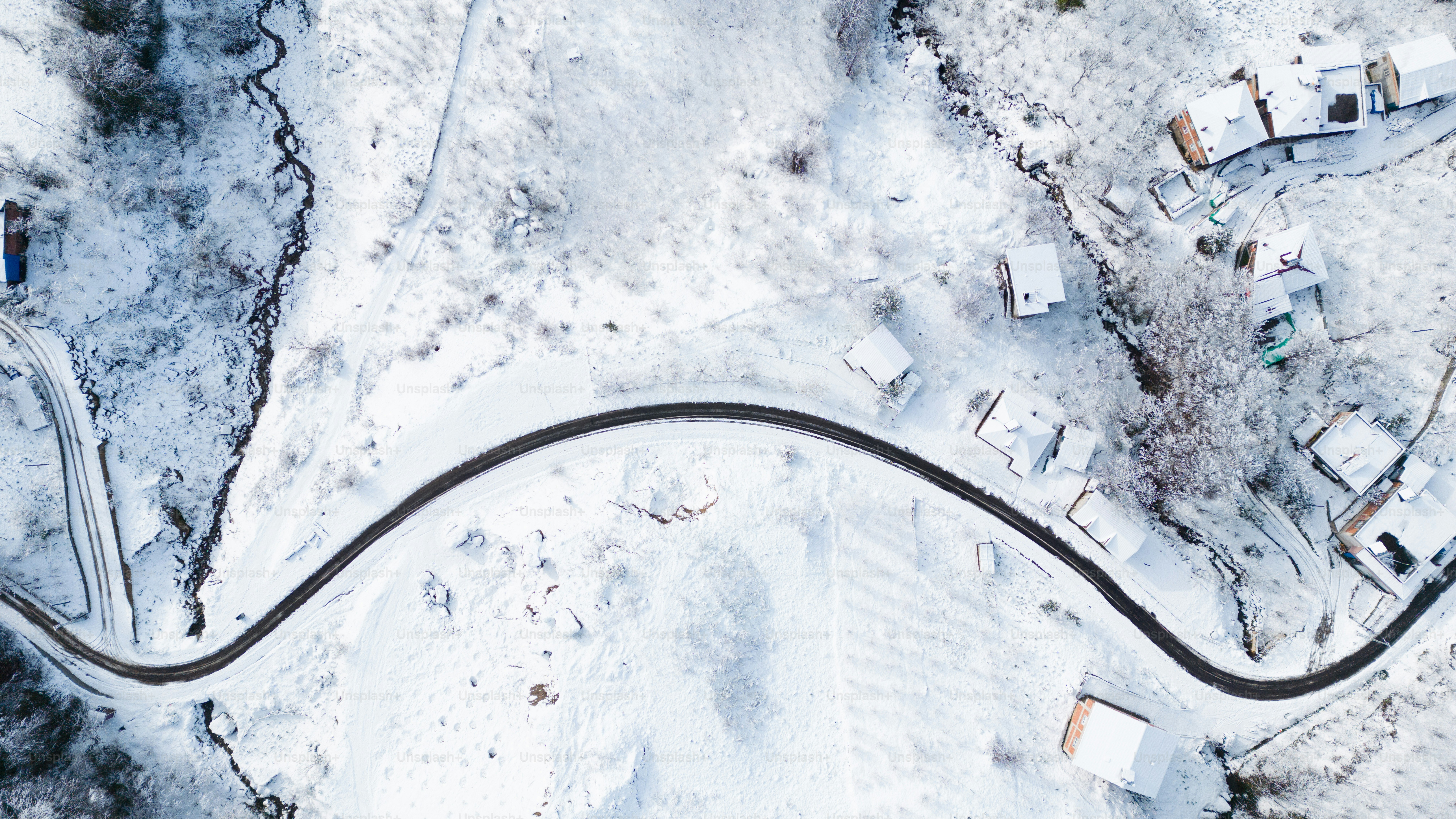 An aerial view of a winding road in the snow photo – Aerial view Image ...