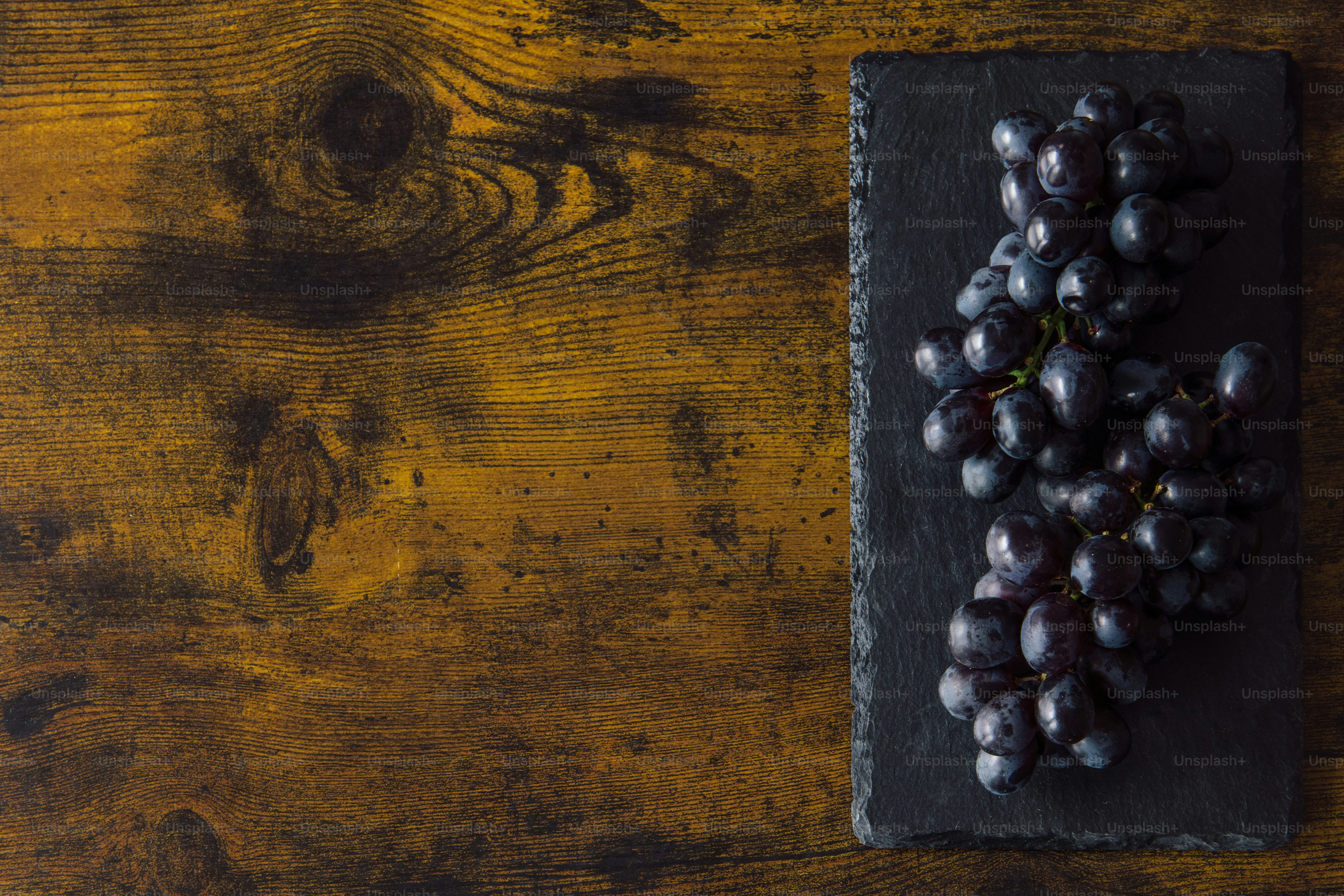 A bunch of grapes sitting on top of a slate slab photo – Cuisine Image ...