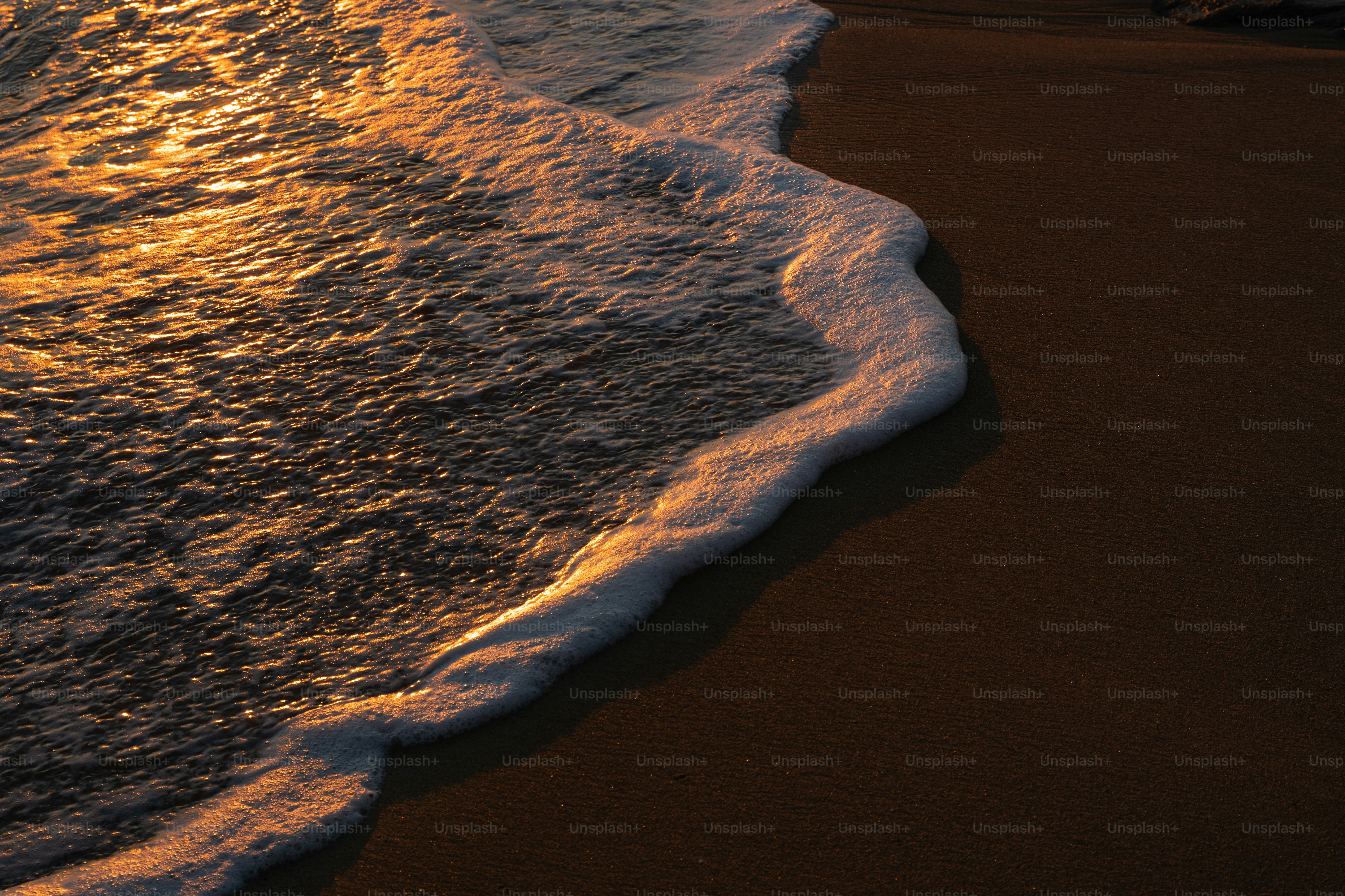 The sun is setting over the ocean with a boat in the distance photo ...