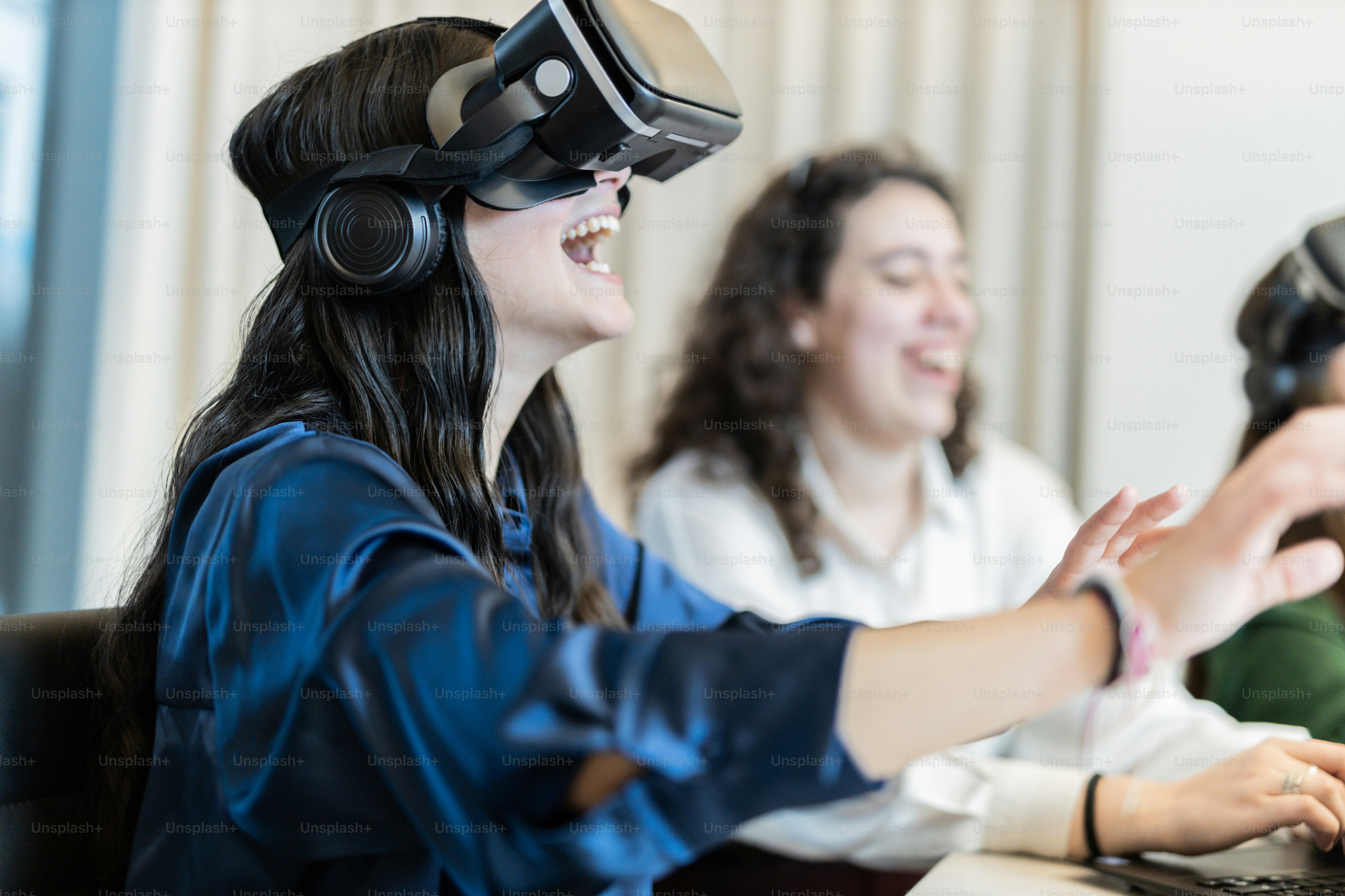 A group of people sitting at a table wearing virtual headsets photo ...