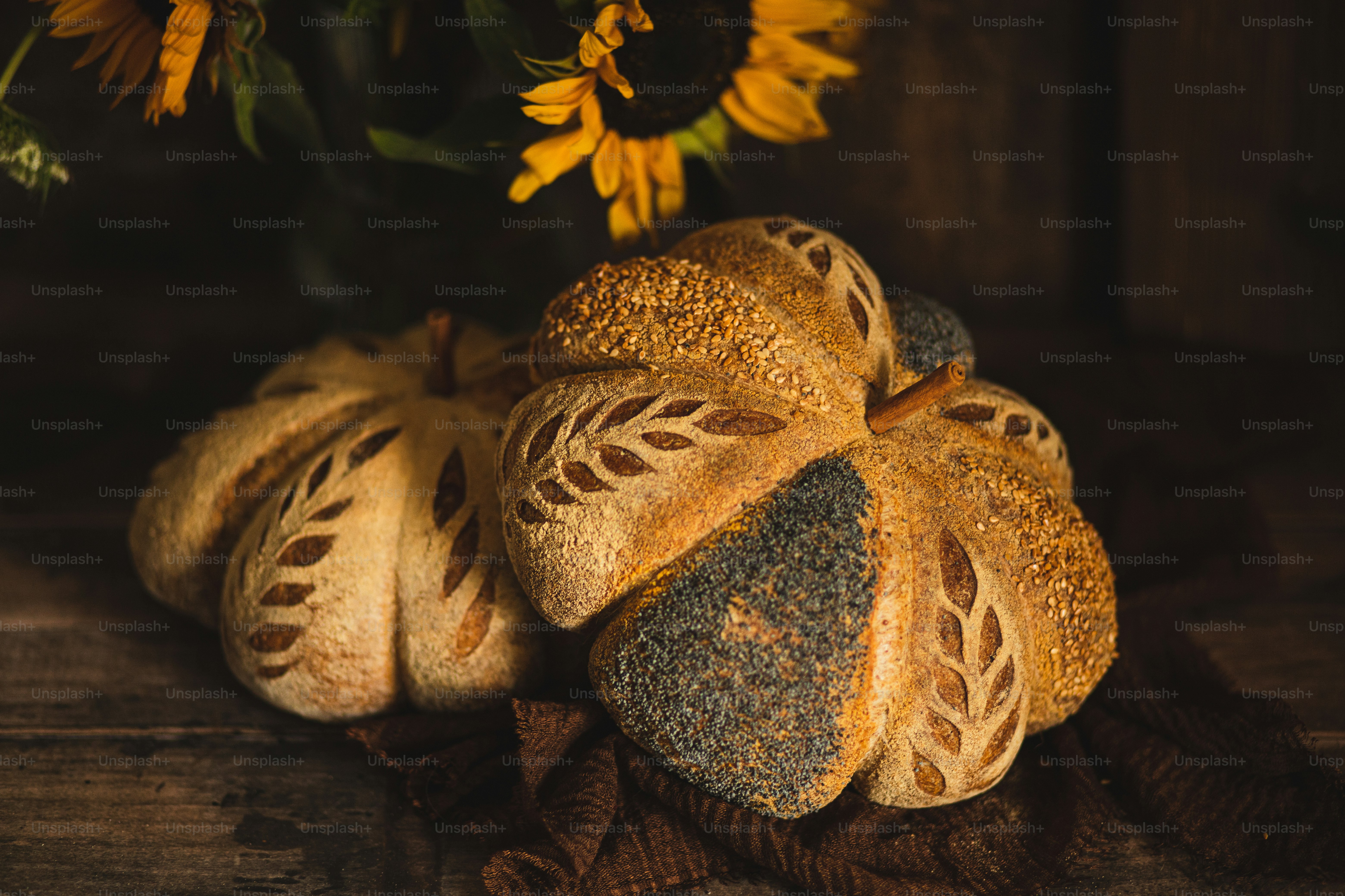 A bunch of loaves of bread sitting next to a vase of sunflowers photo ...