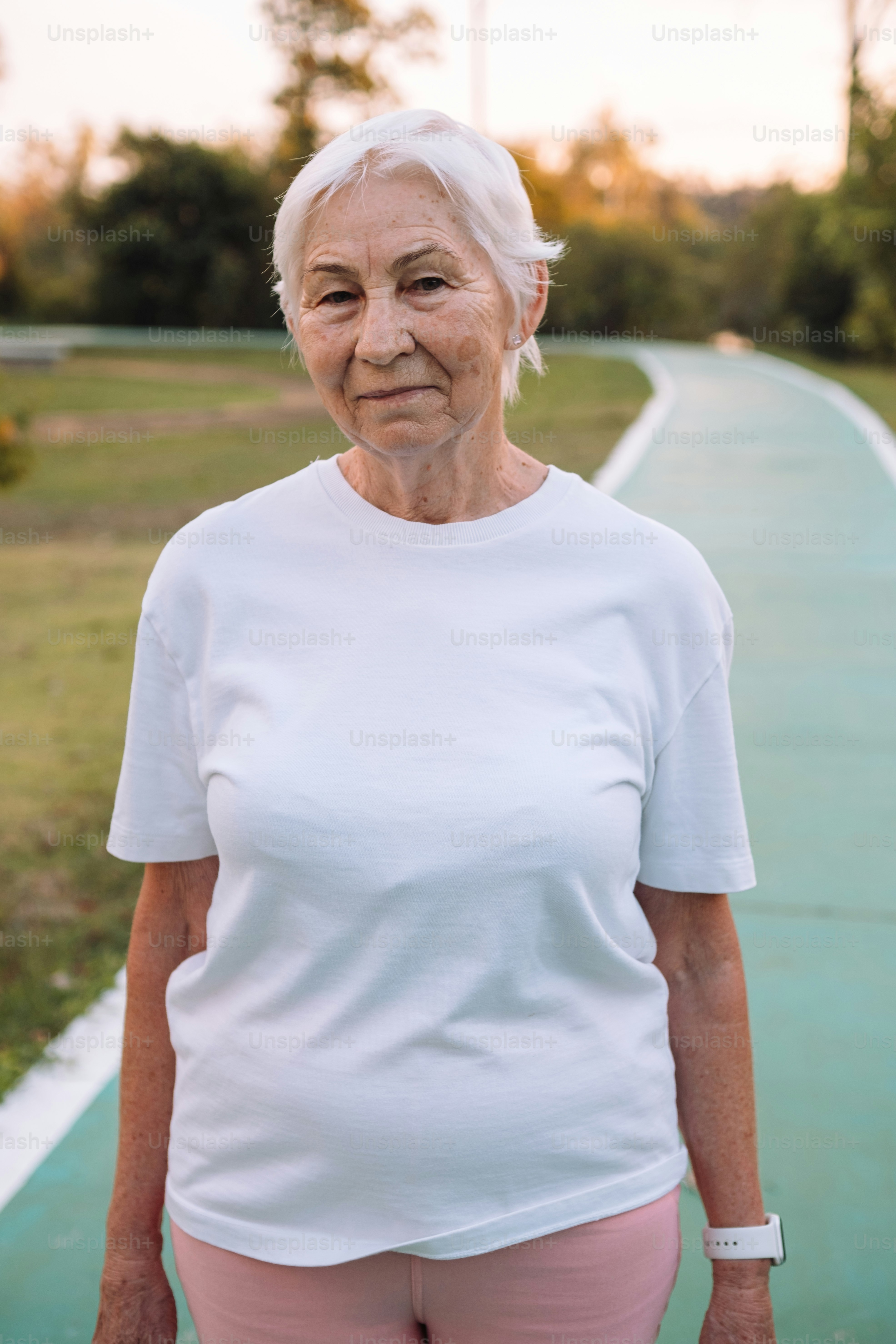 Foto Una mujer mayor parada en un sendero en un parque – Abuelos Imagen ...