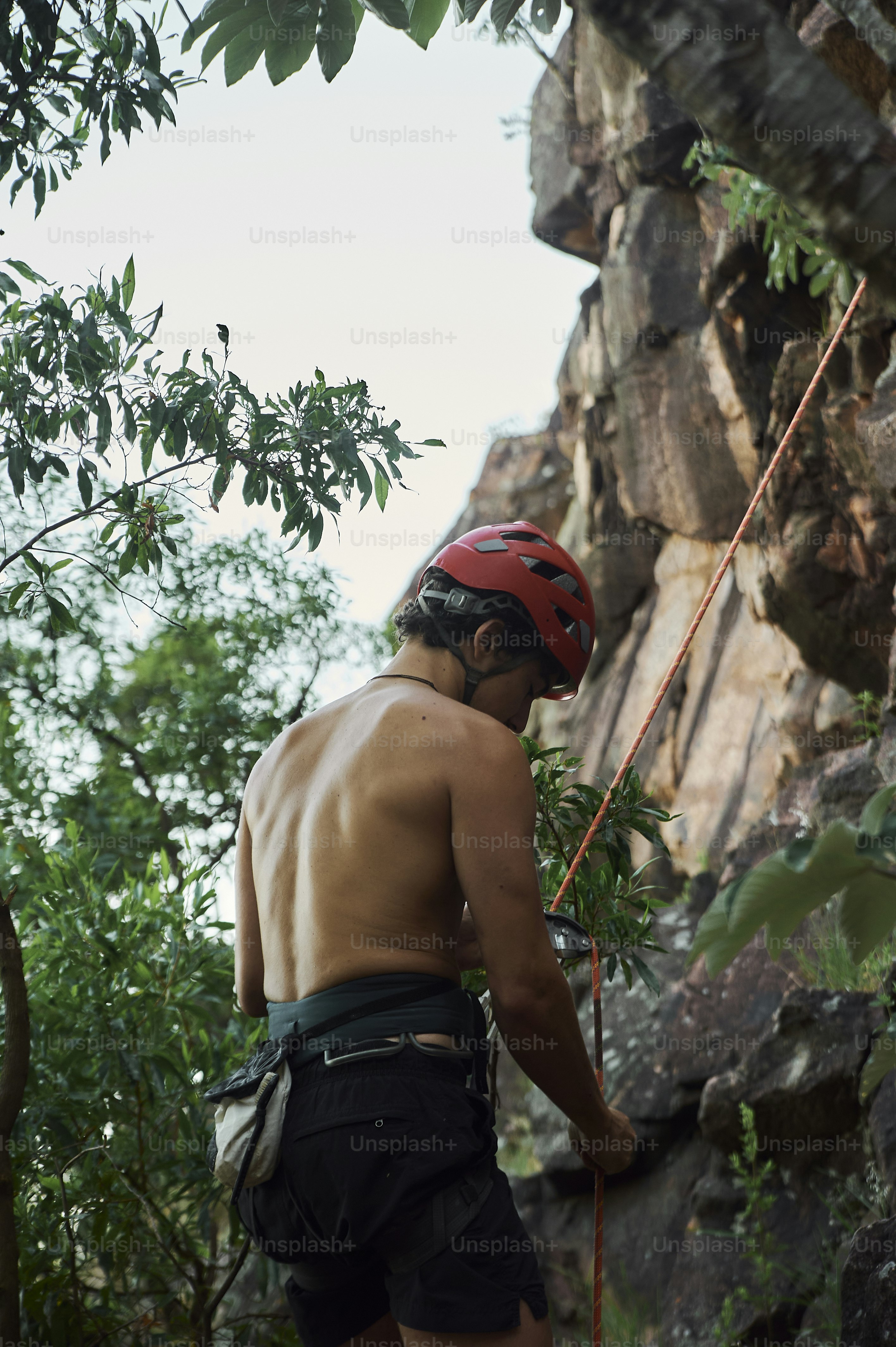 A shirtless man climbing up the side of a mountain photo – Rock ...