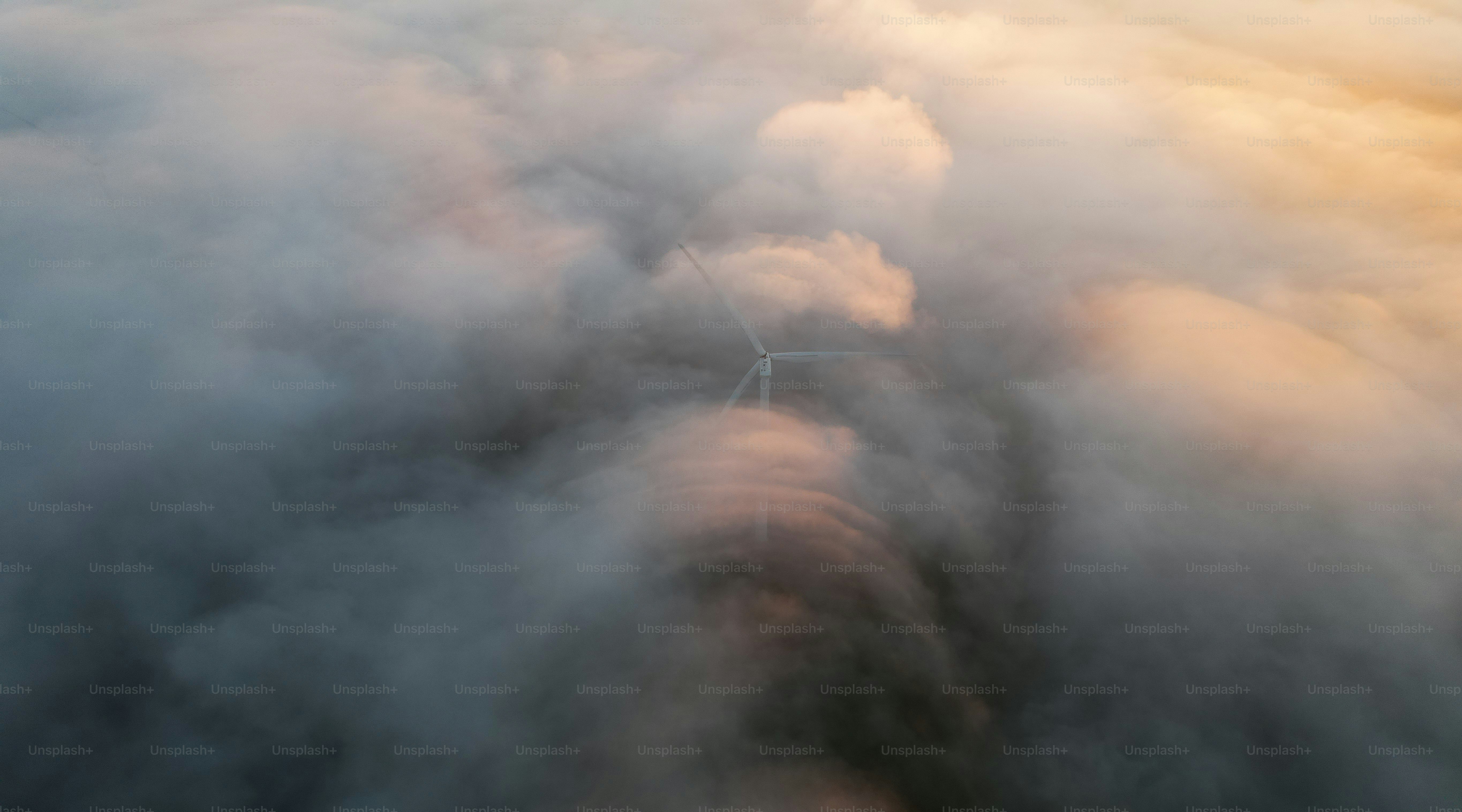 An aerial view of a wind turbine surrounded by clouds photo – Windmill ...