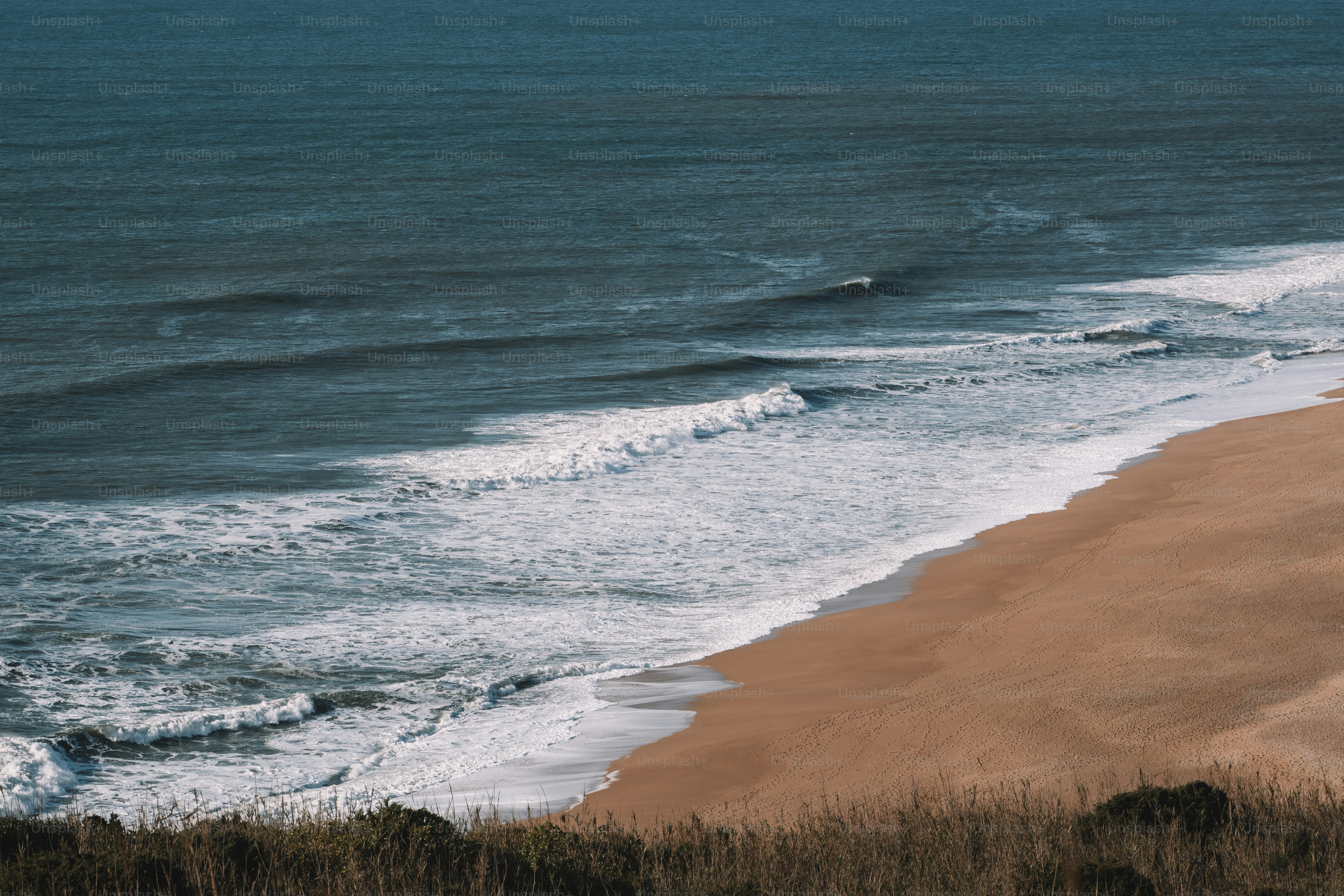 A sandy beach with waves coming in to shore photo – Atlantic ocean ...