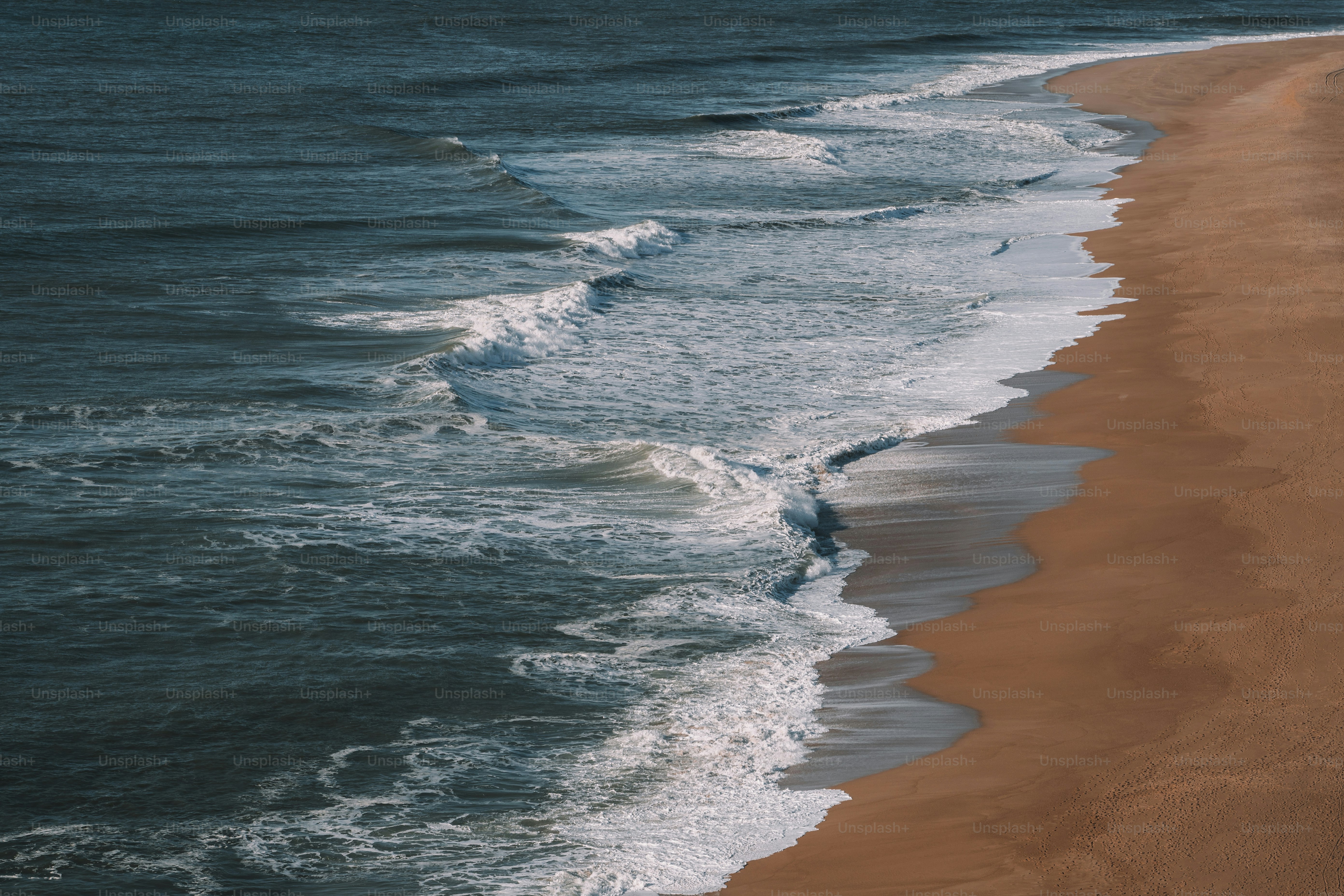 A view of a beach with waves coming in from the ocean photo – Waves ...
