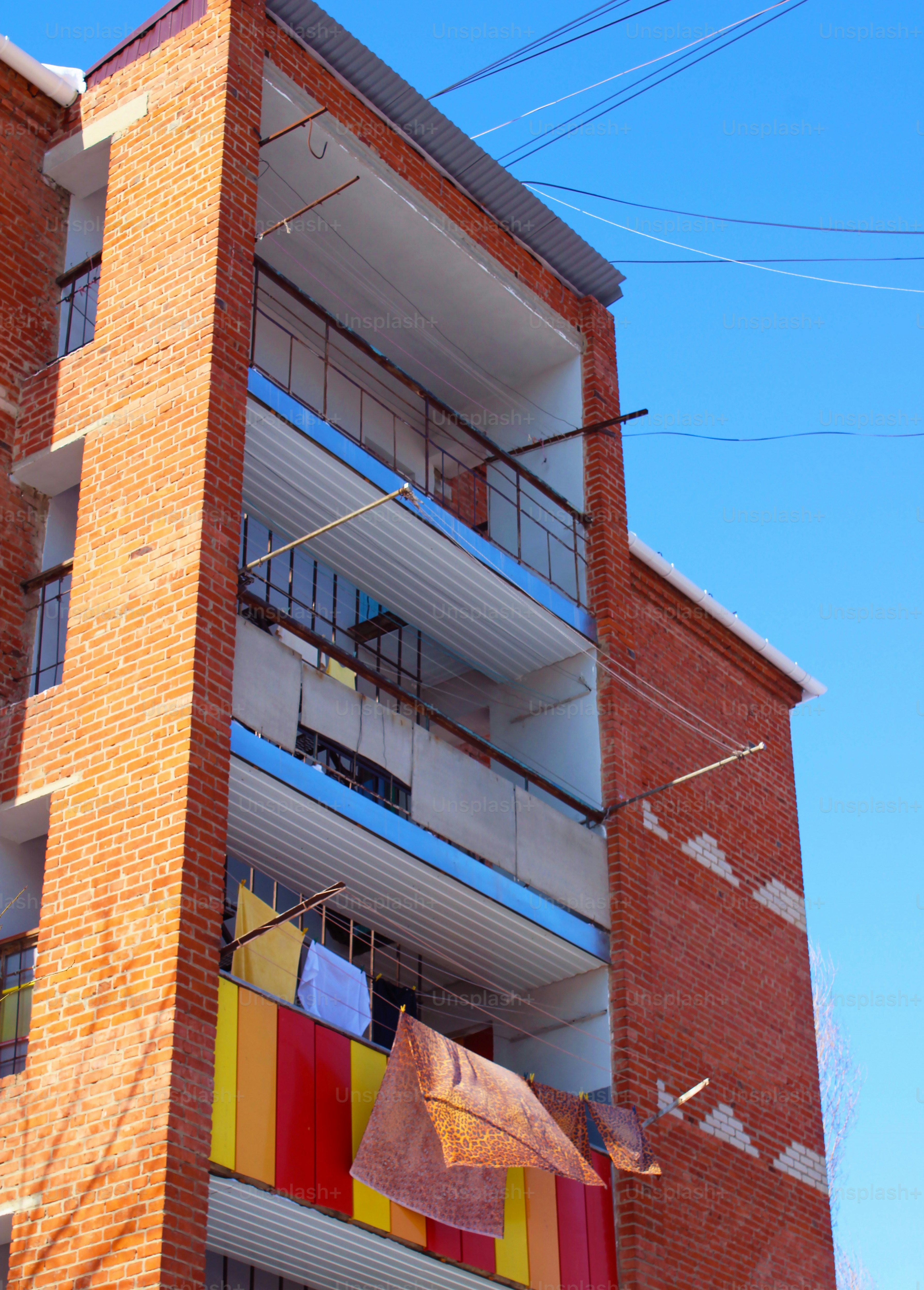 A tall brick building with a multi - colored balcony photo – Apartament ...