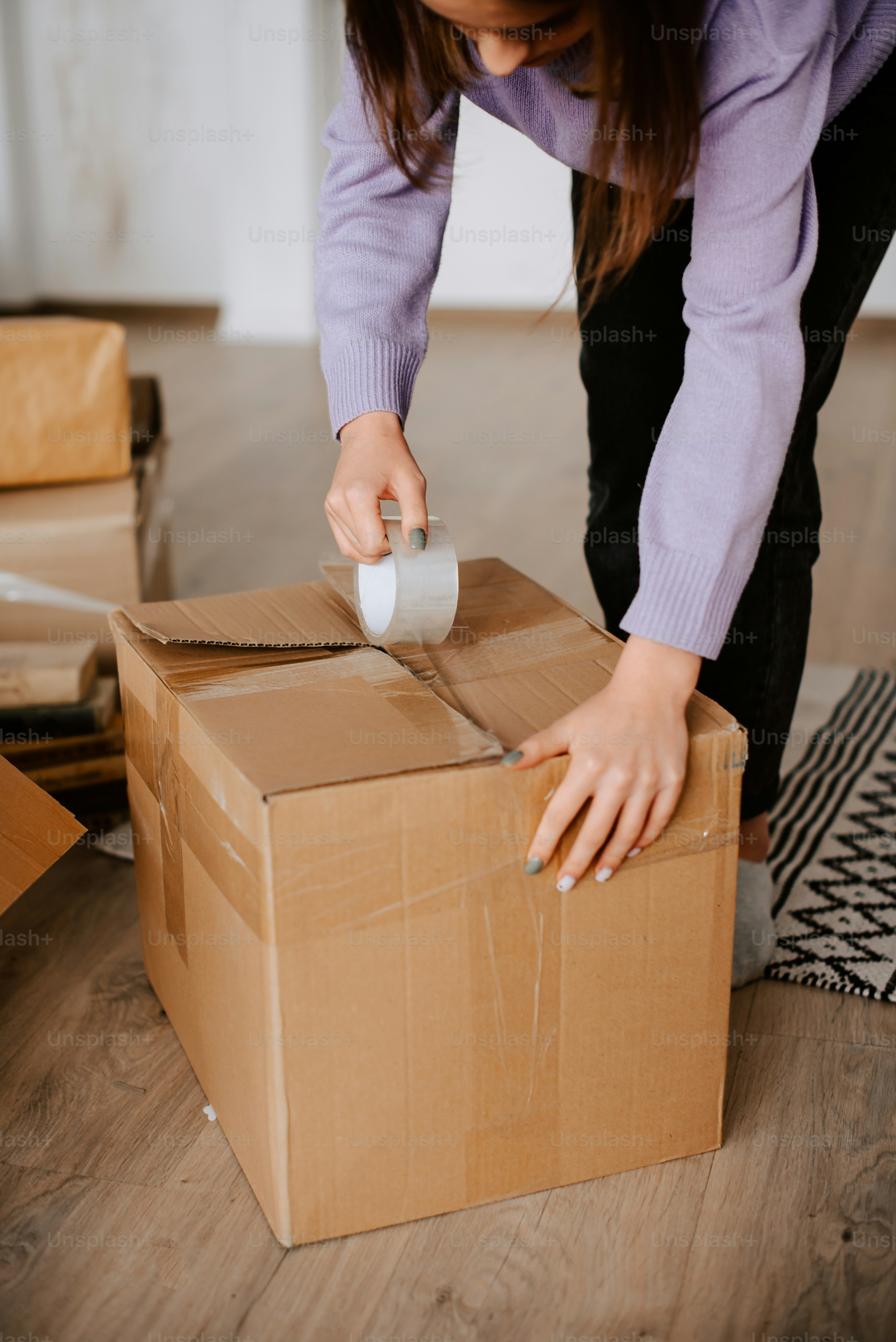 A woman is wrapping a box on the floor photo – Carton Image on Unsplash